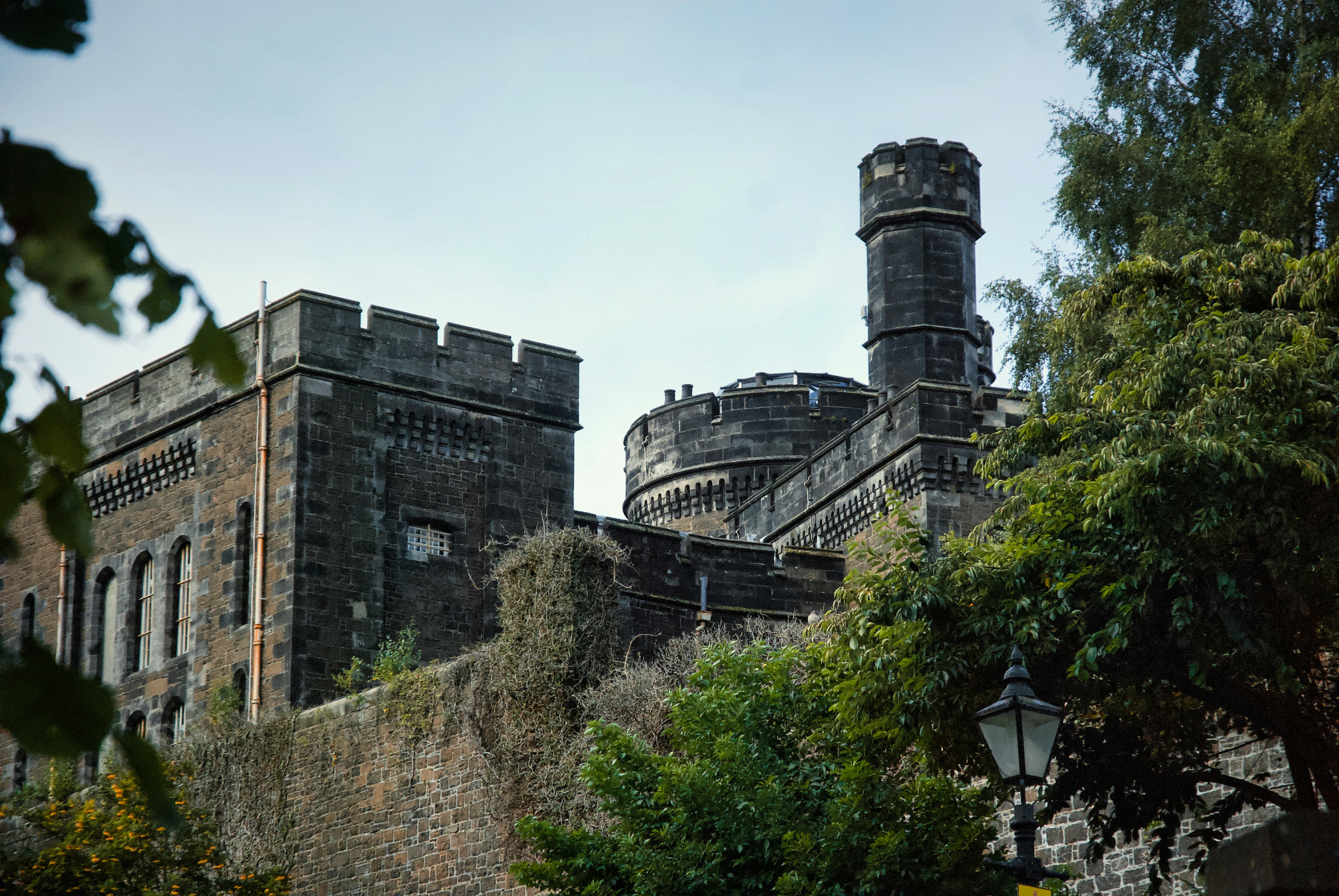 Stone castle with round tower and trees.