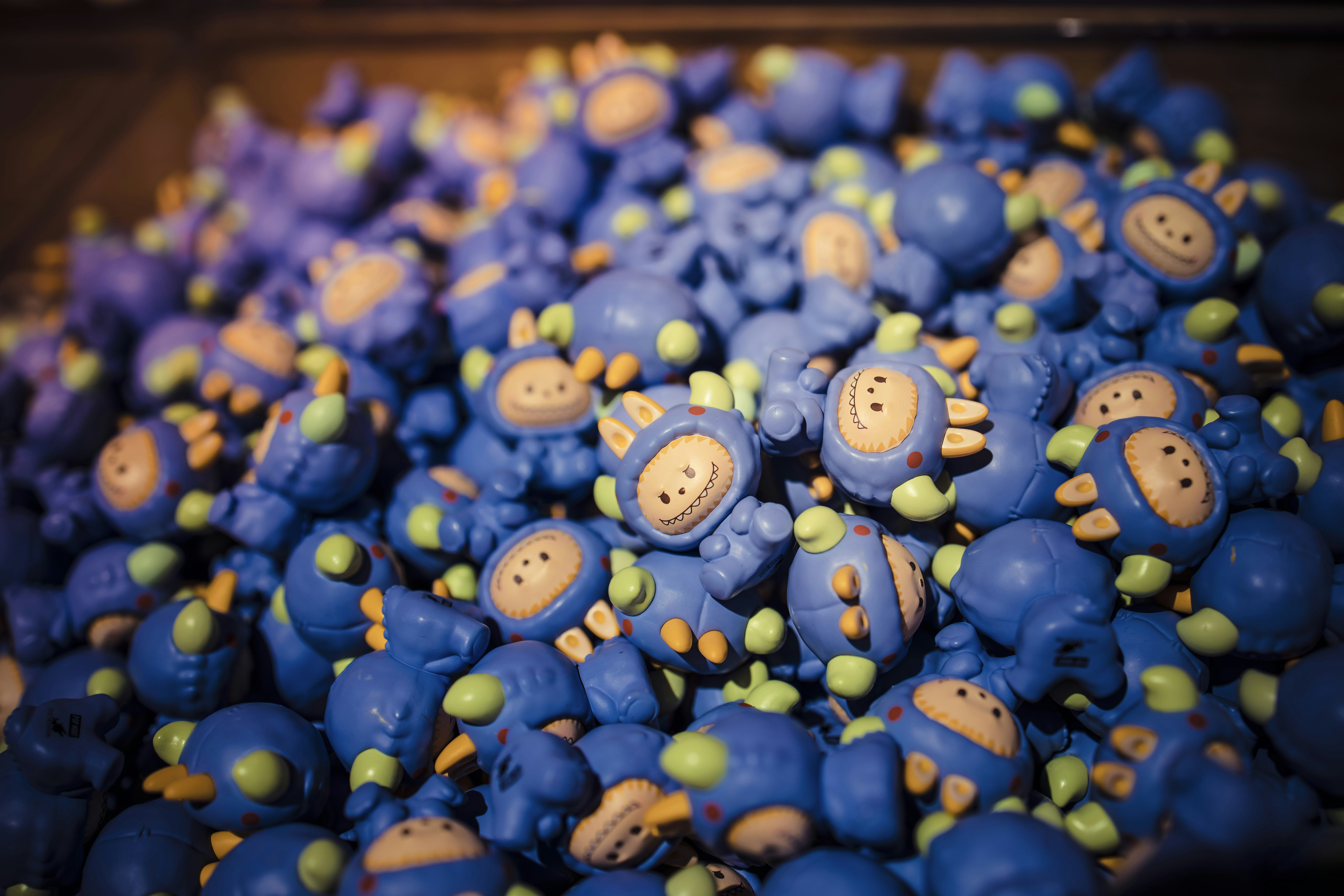 A vibrant collection of small blue figures with playful designs, featuring green accents and expressive faces. The scene is filled with these charming characters, creating a delightful visual experience.