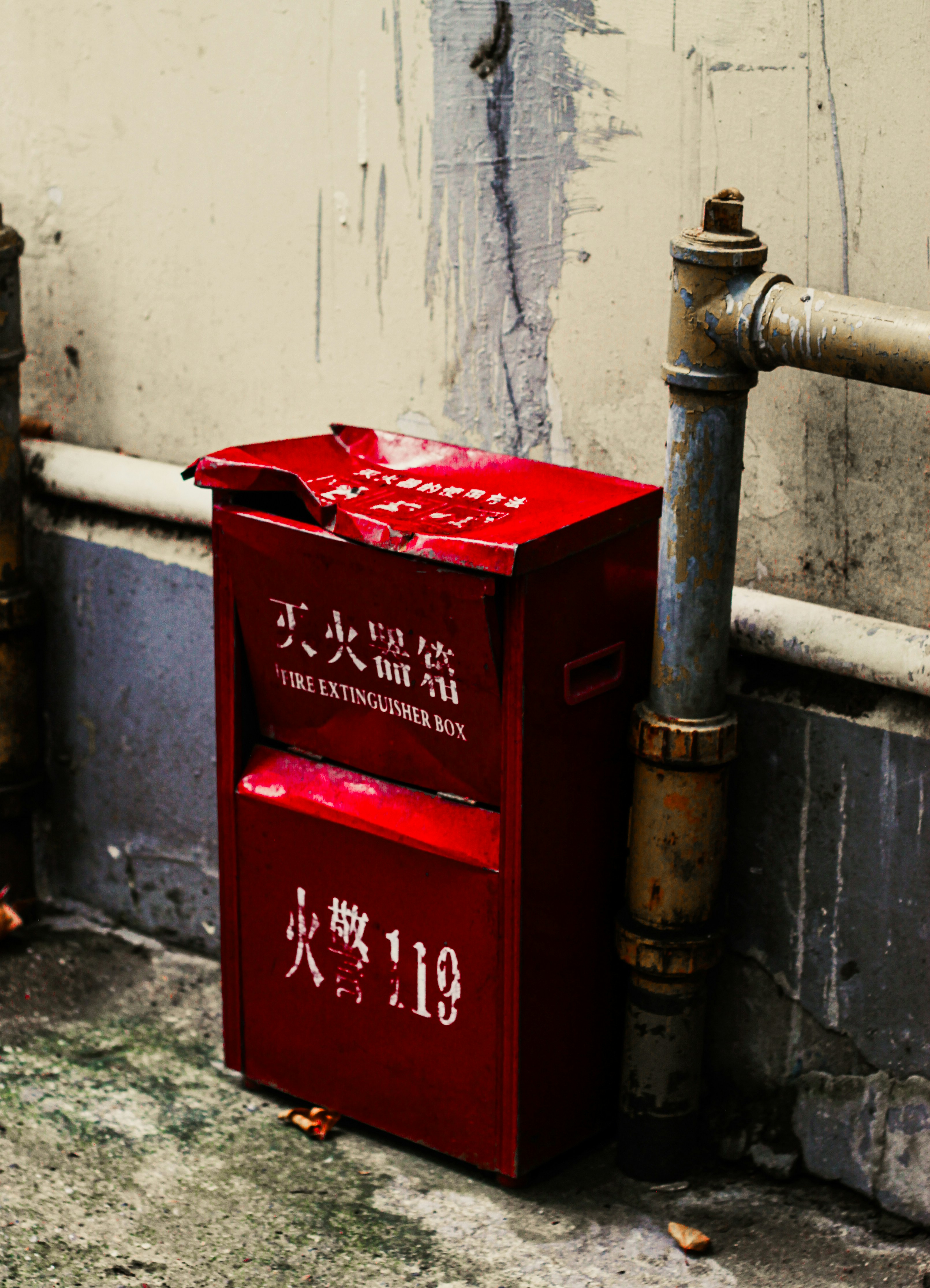 Red fire extinguisher box next to pipe