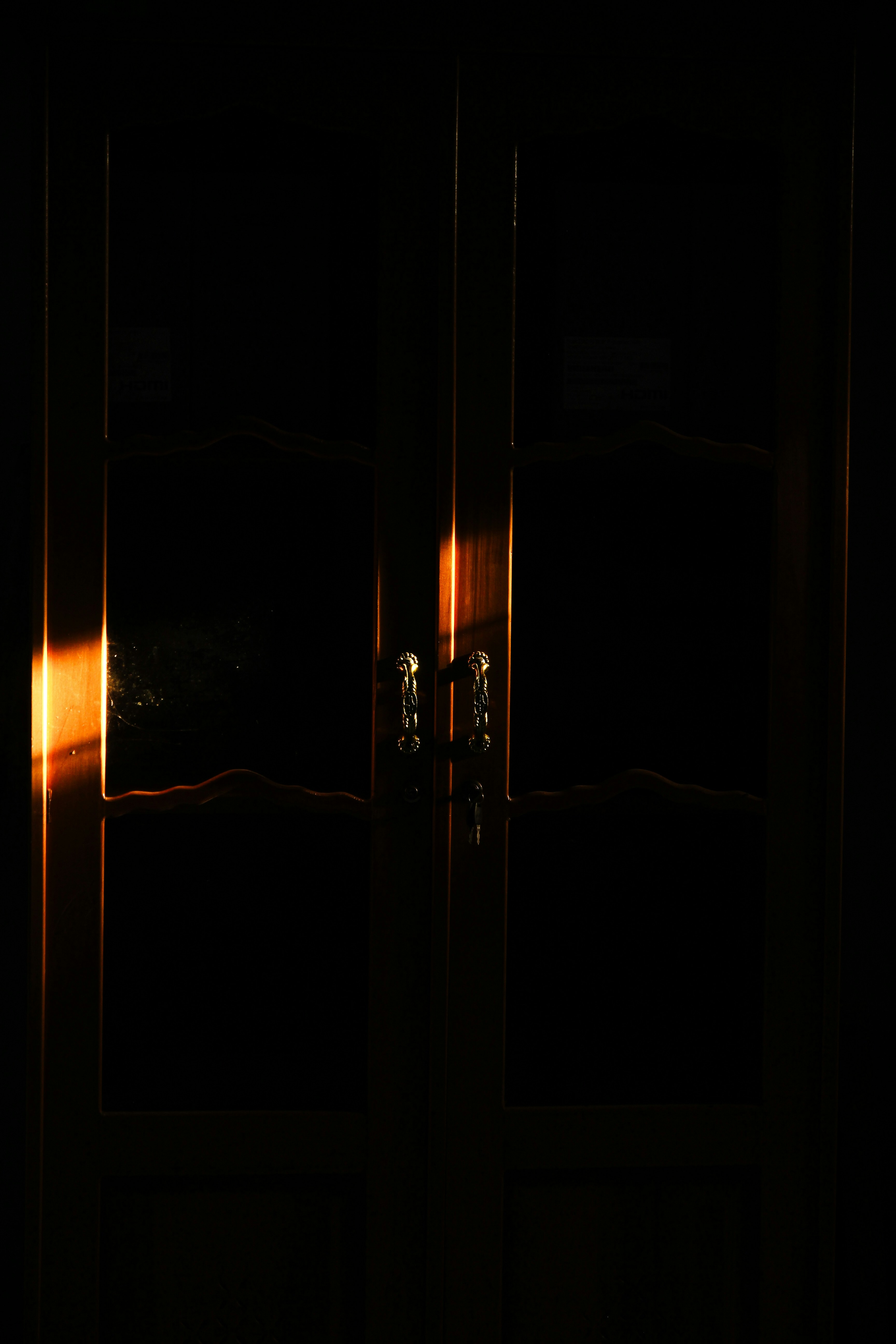 The cupboard was exposed to light | Dark wooden doors with warm light shining through