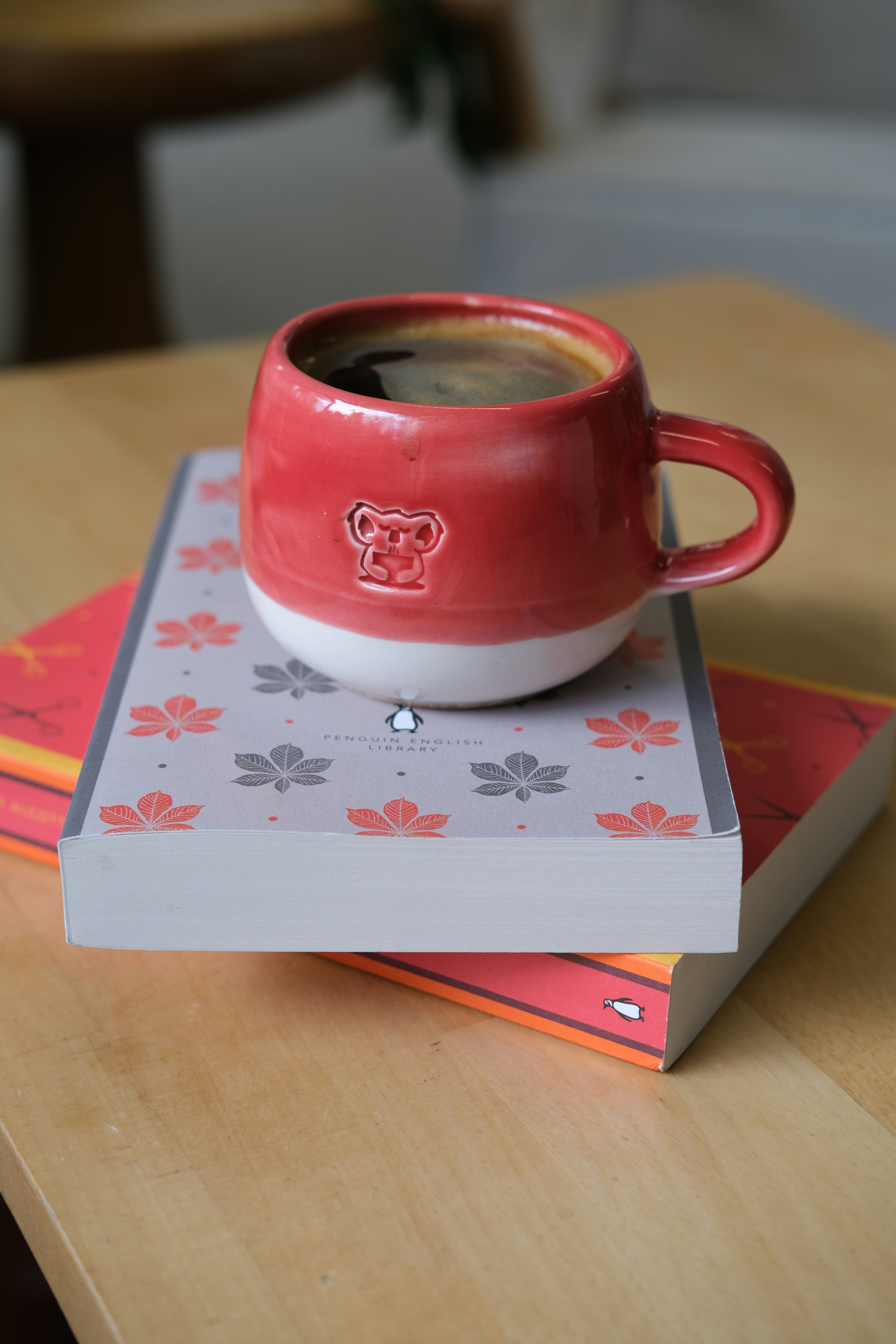 Crimson Coffee Cup Resting on Floral-Patterned Book Stack