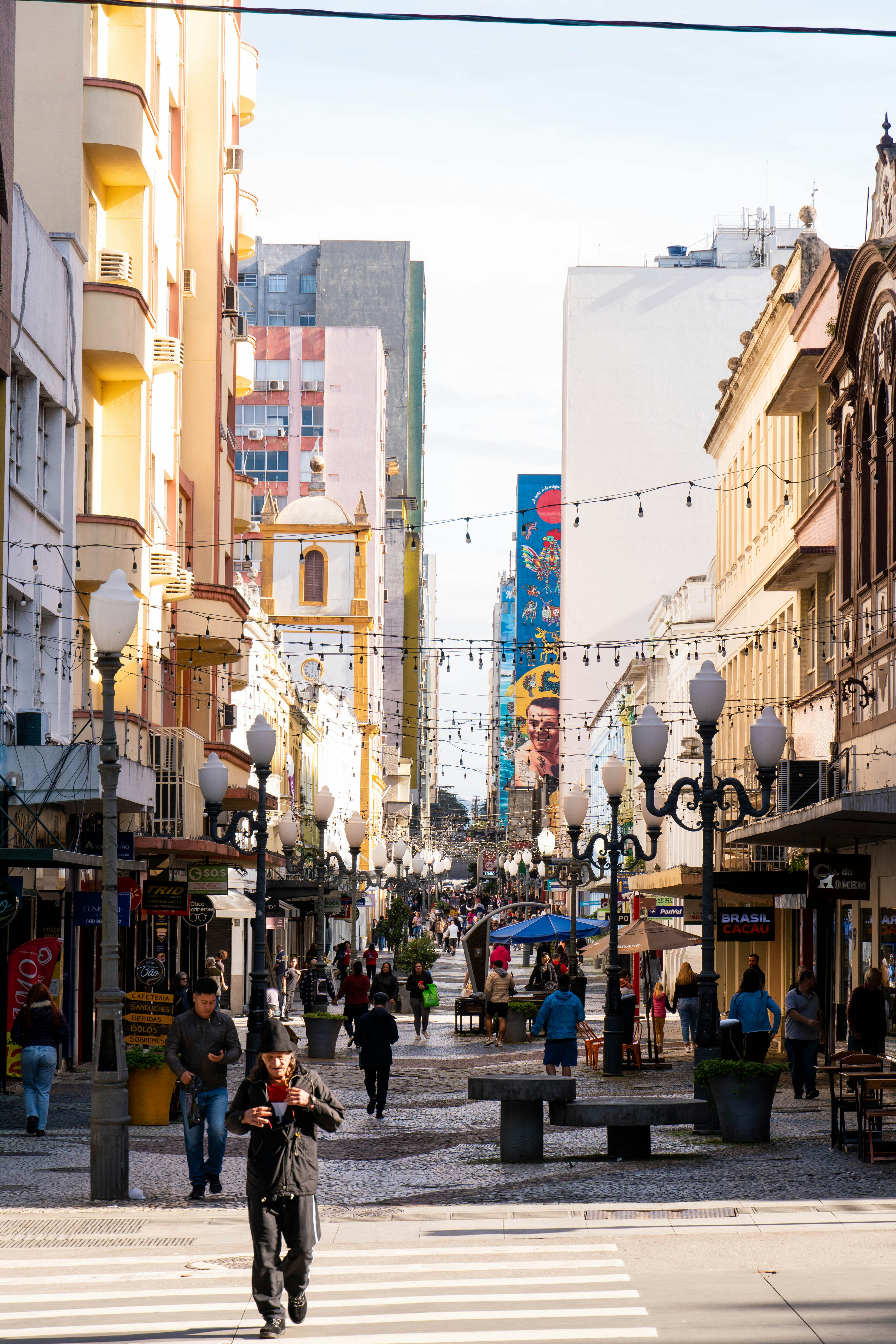 People walking down a pedestrian street with buildings.