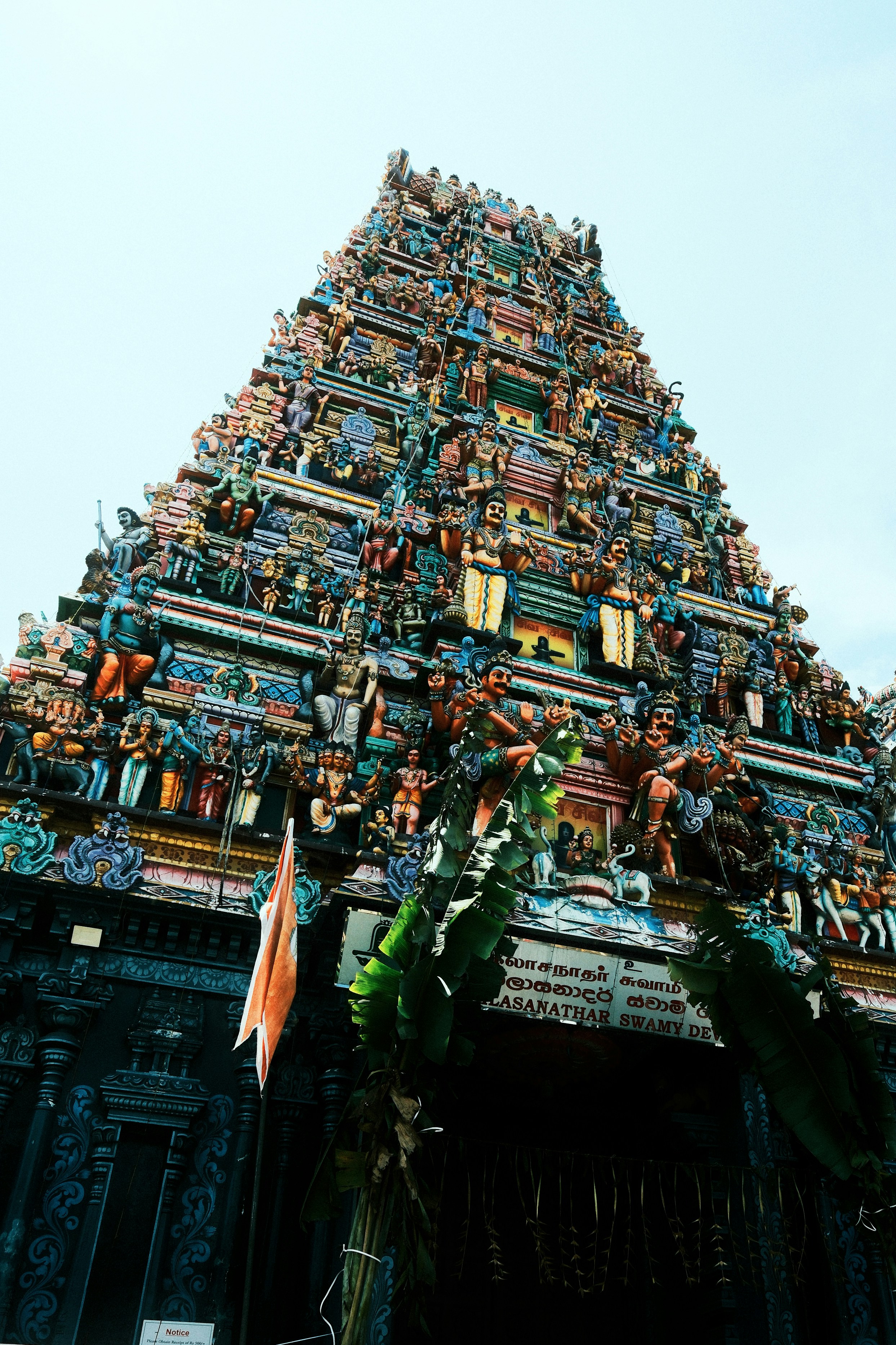 Intricately carved temple tower adorned with vibrant sculptures of deities and mythological figures, showcasing rich cultural artistry.