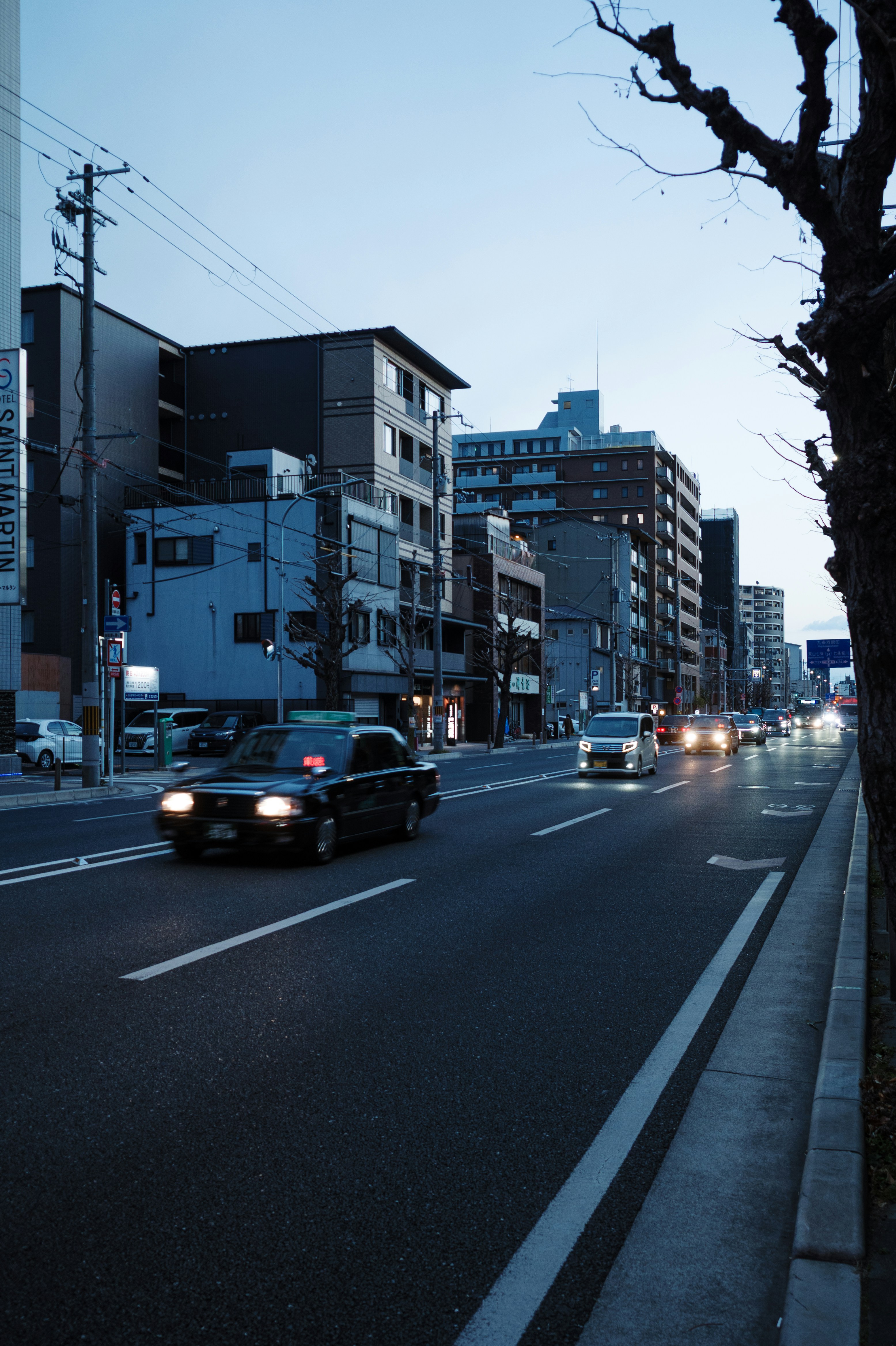 Cars driving on a city street at dusk.
