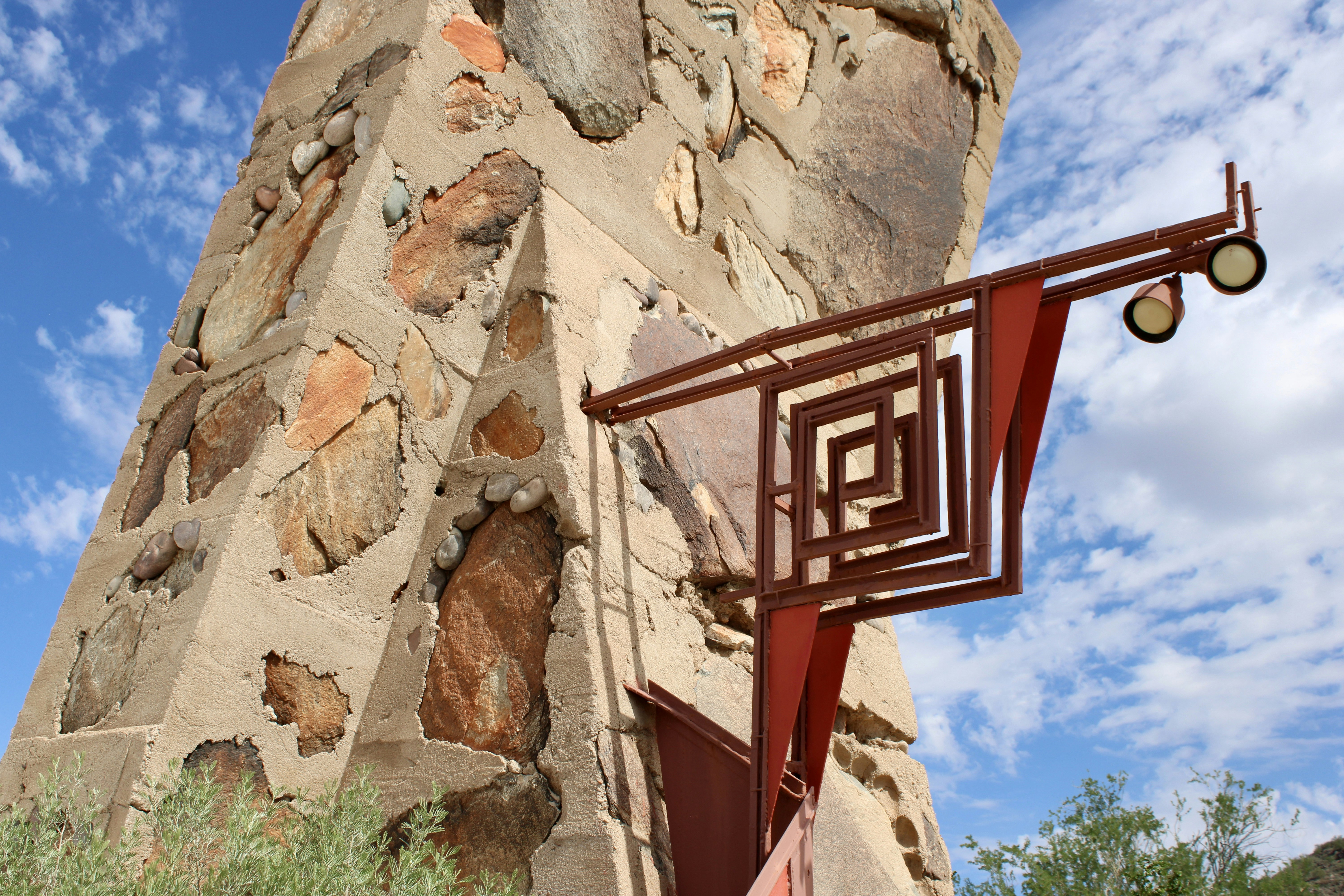 Decorations at Taliesin West | Stone tower with abstract metal sculpture against sky