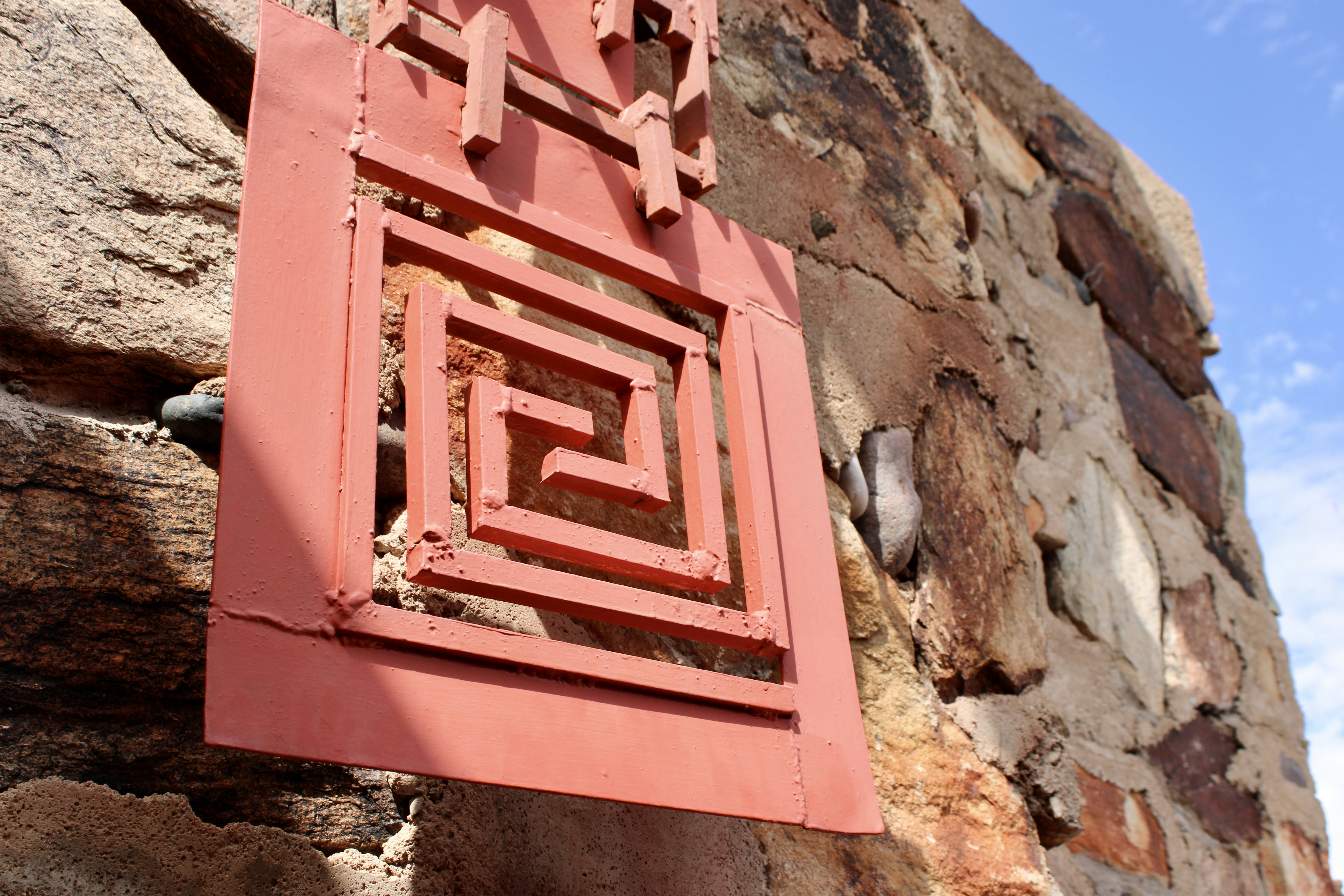 Rust-Red Spiral Frame Clinging to Weathered Stone