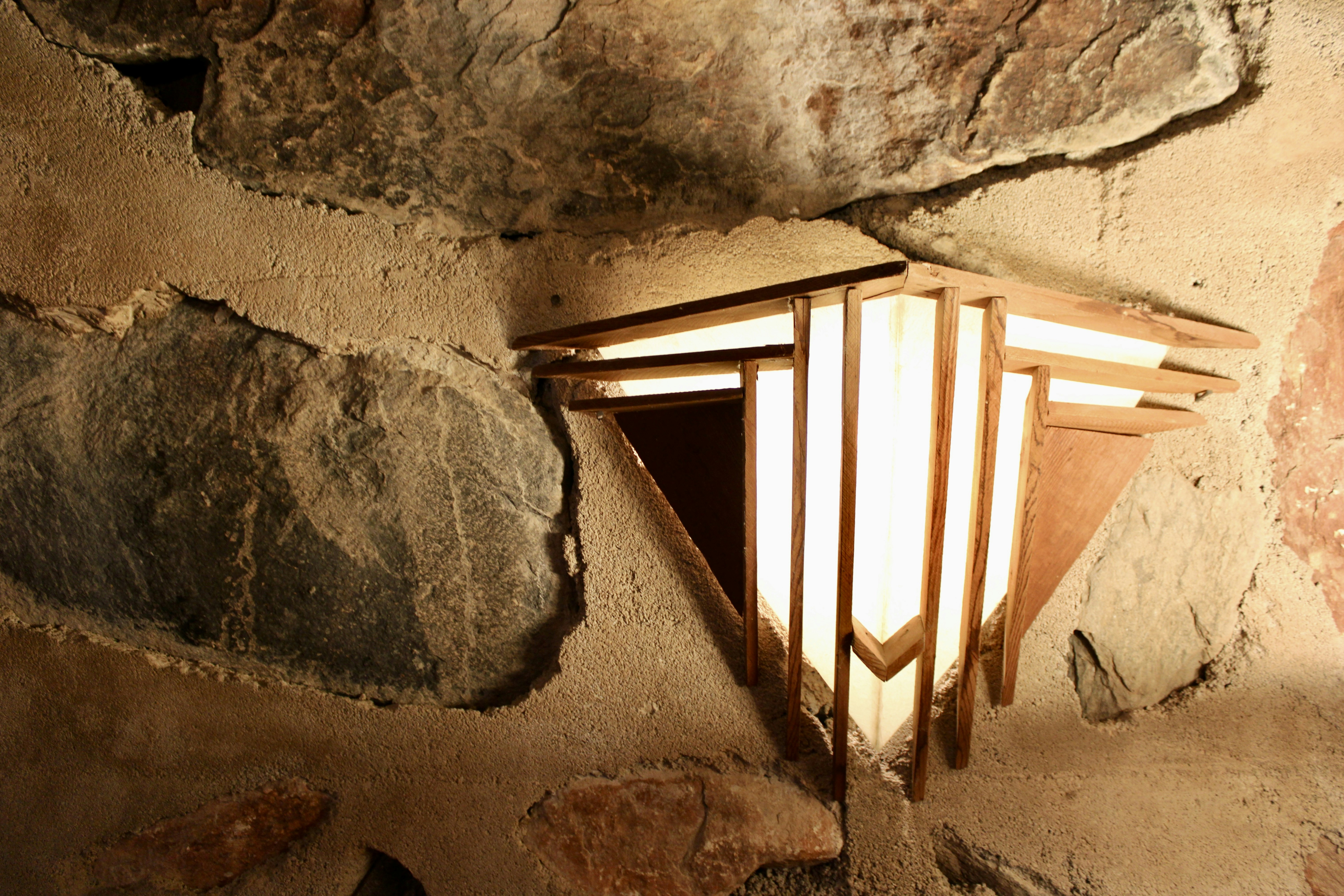 Sconce at Taliesin West | A rustic stone wall with a geometric light fixture.