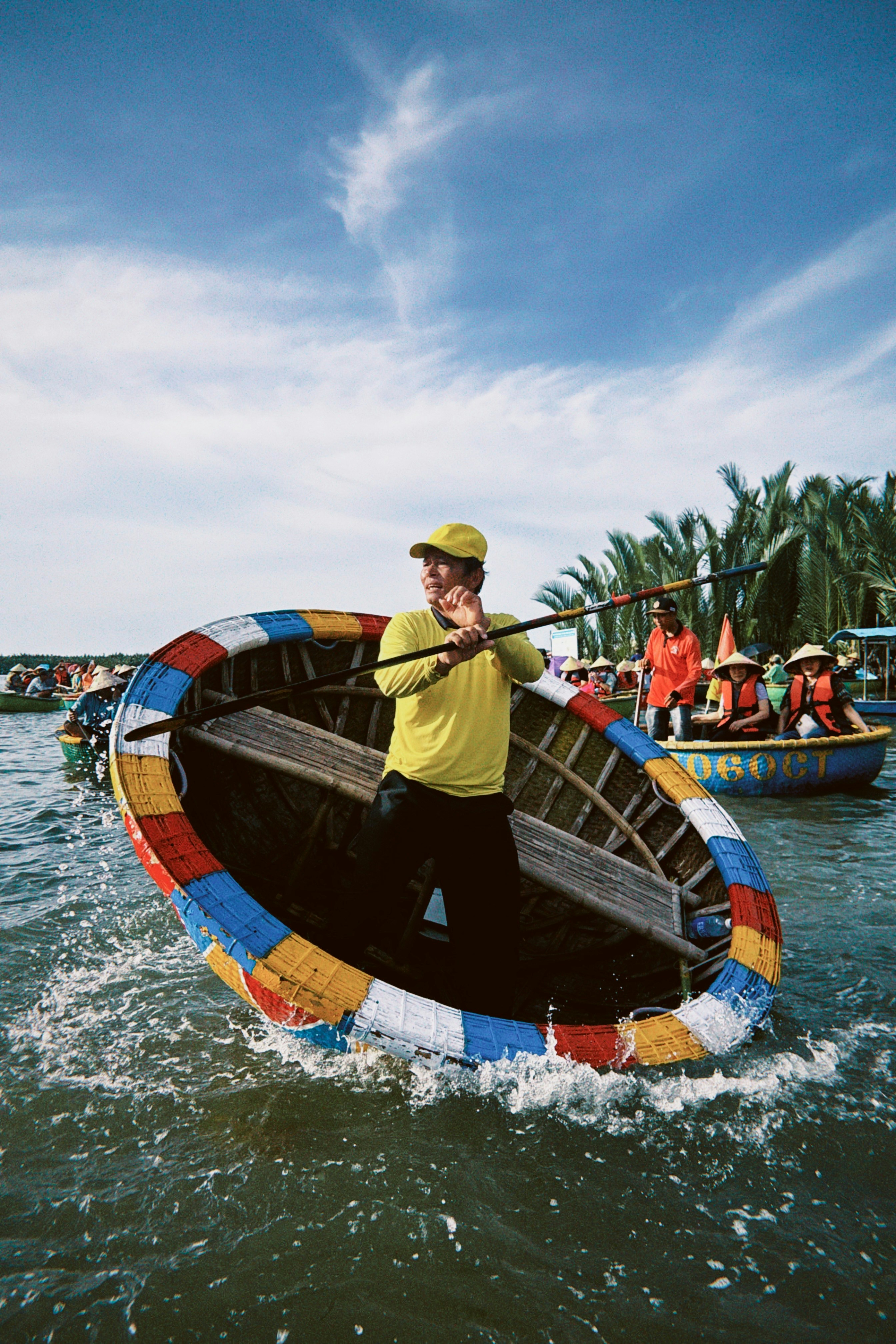 Man paddles a colorful round boat on water