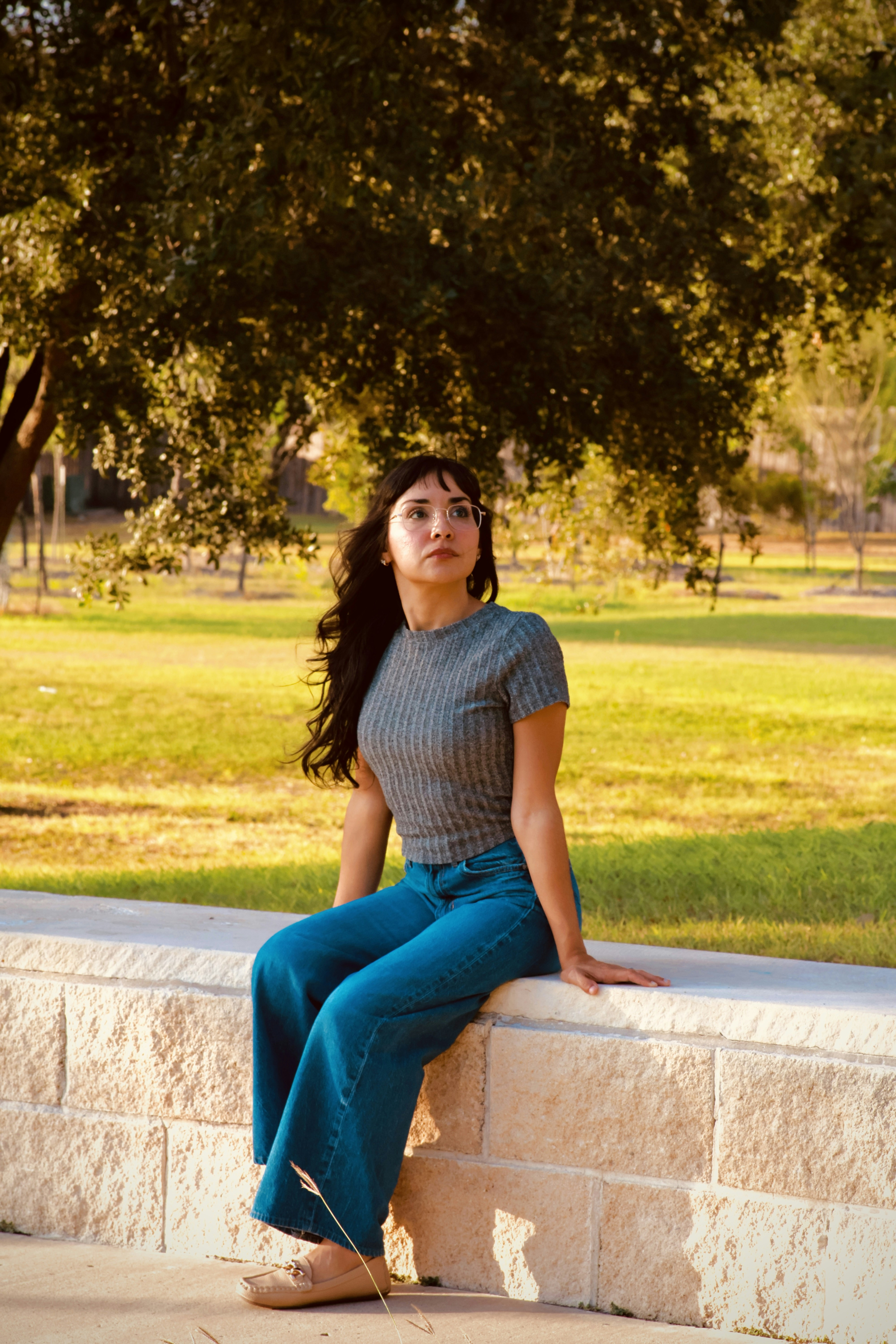 Young woman sitting on a stone wall outdoors.