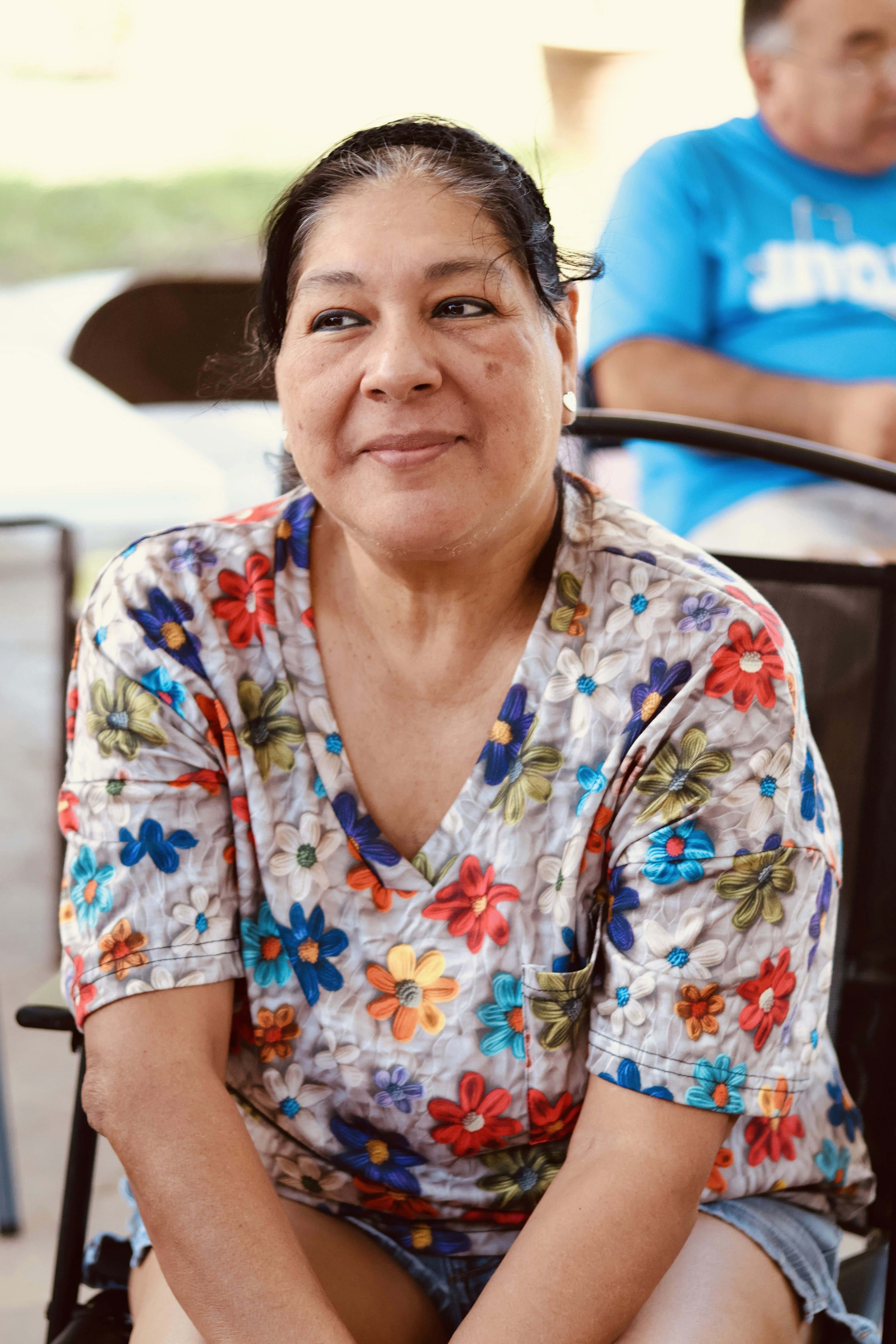Woman in a floral shirt smiles outdoors