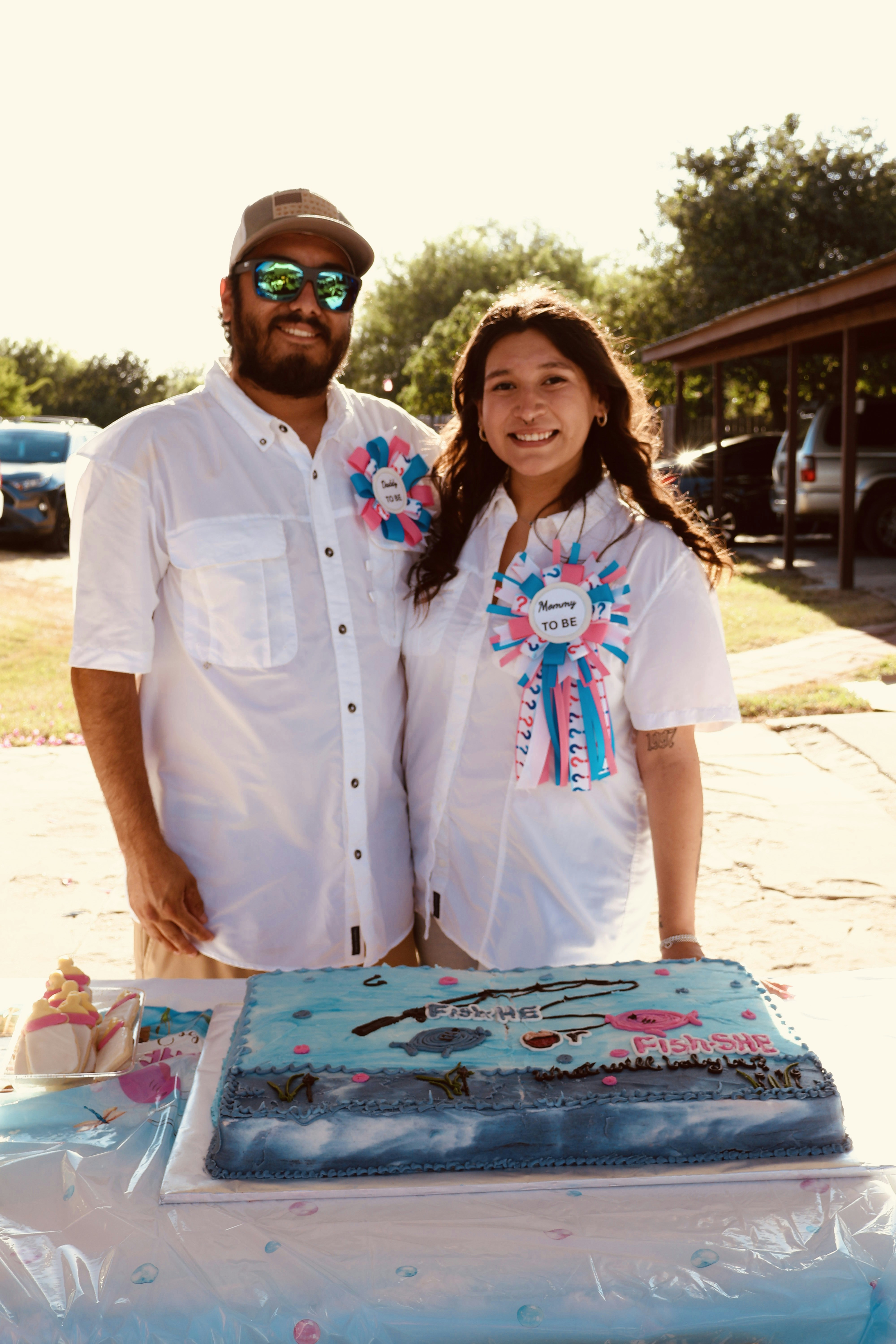 Couple with gender reveal cake and decorations