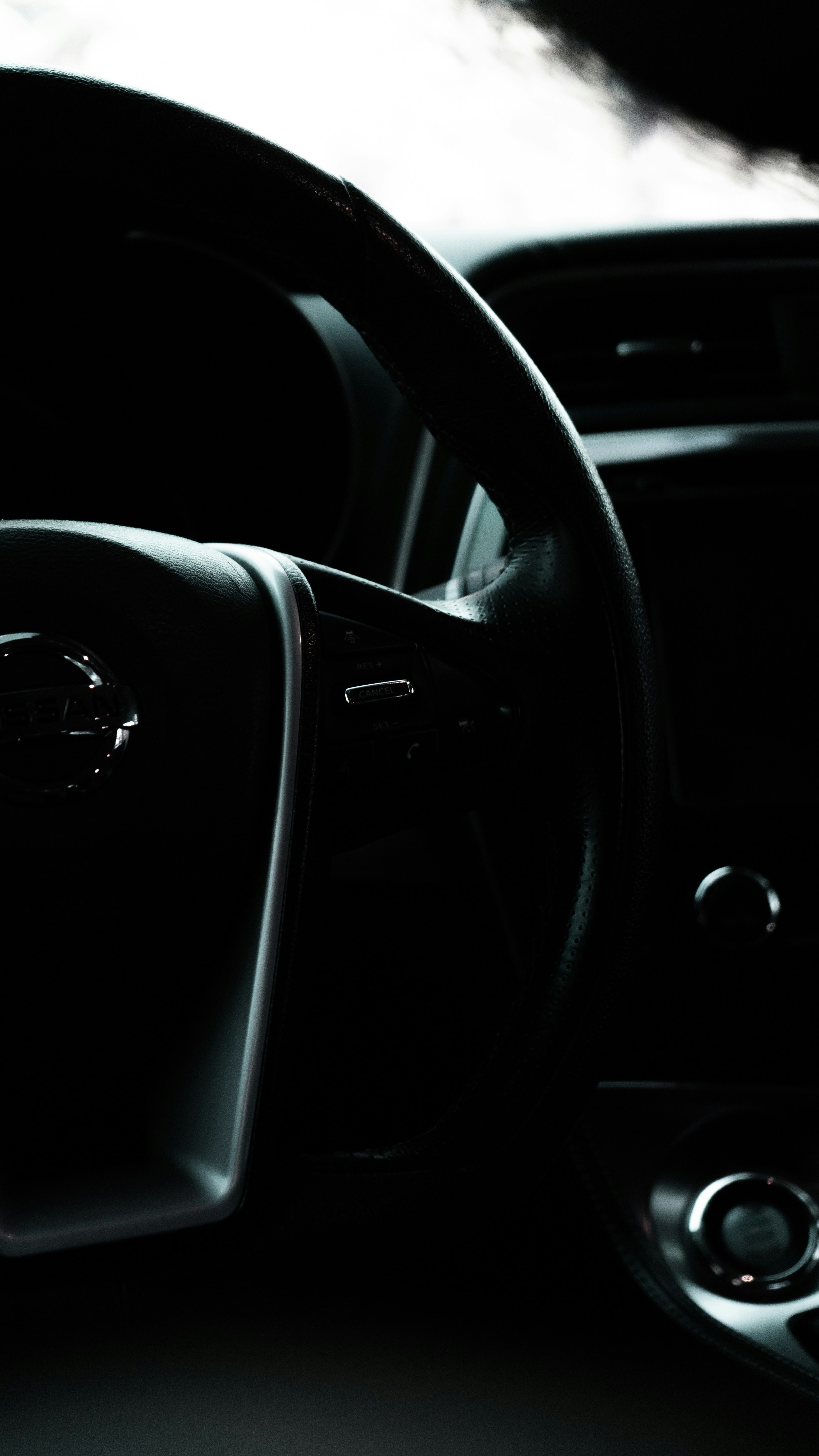 Close-up of a car's steering wheel with a blurred dashboard, emphasizing the sleek design and functionality of automotive interiors.