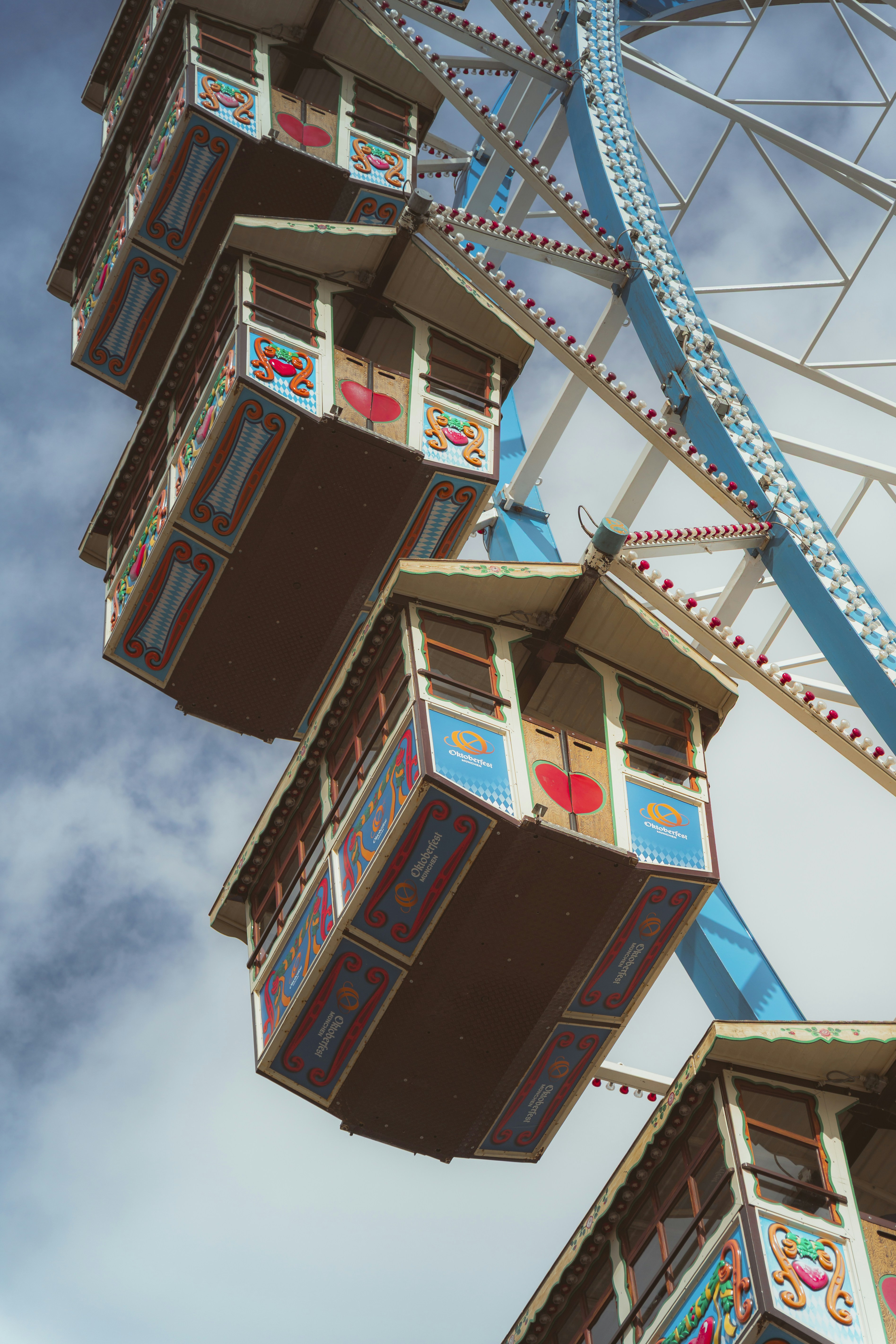 Colorful gondolas of a vintage Ferris wheel against a blue sky, showcasing intricate designs and playful details.