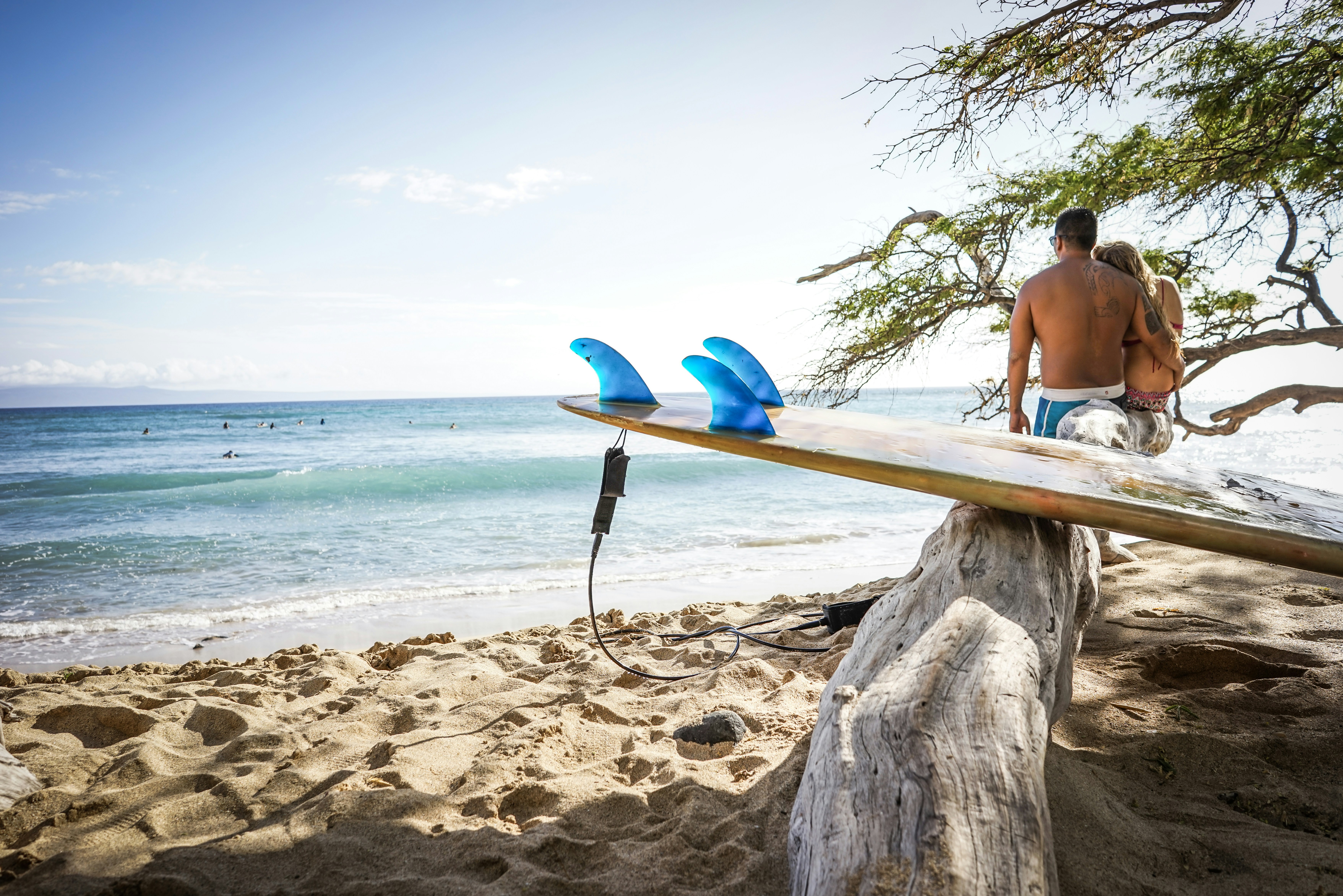 Couple sitting on beach with surfboard