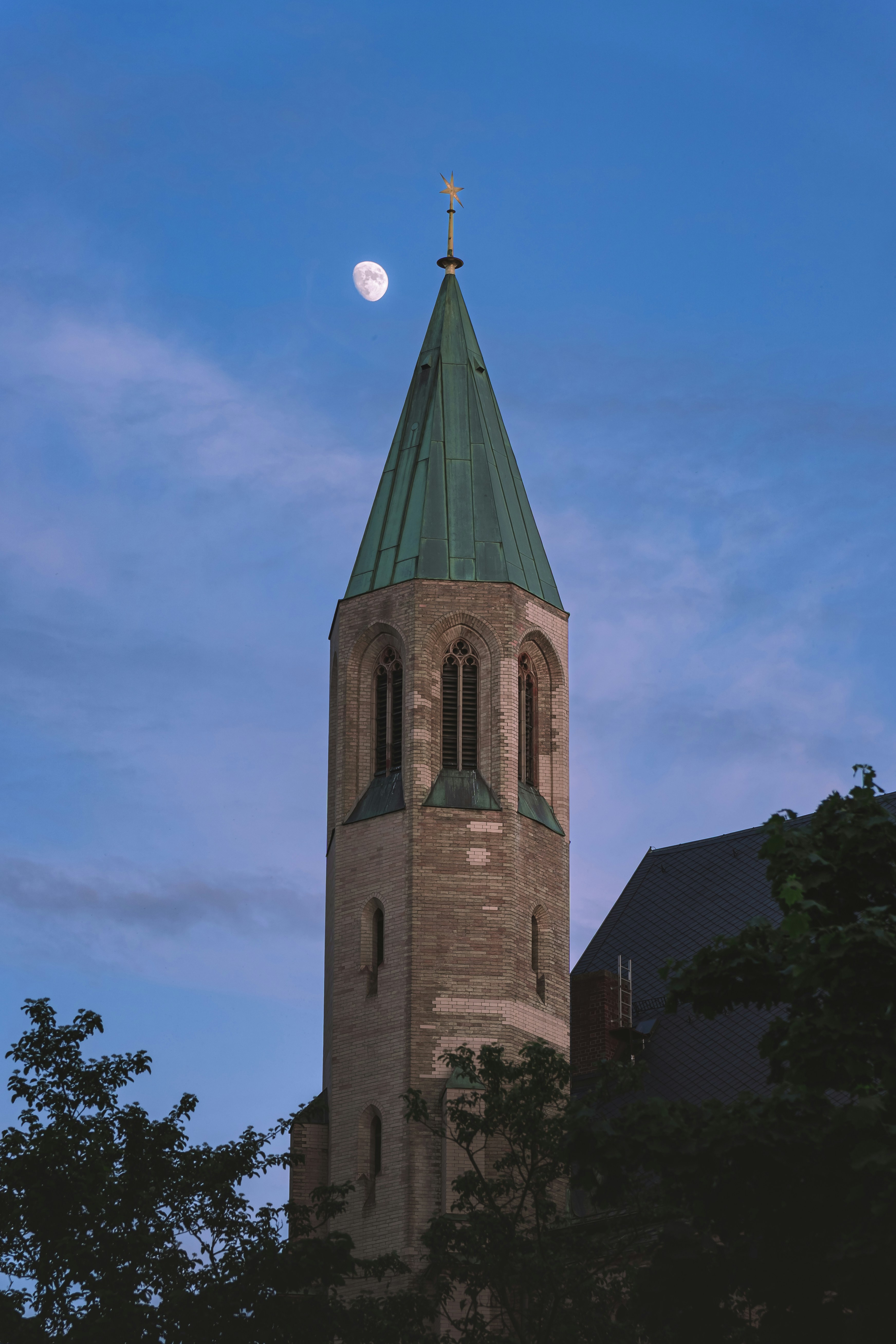 Church tower with moon in blue twilight sky