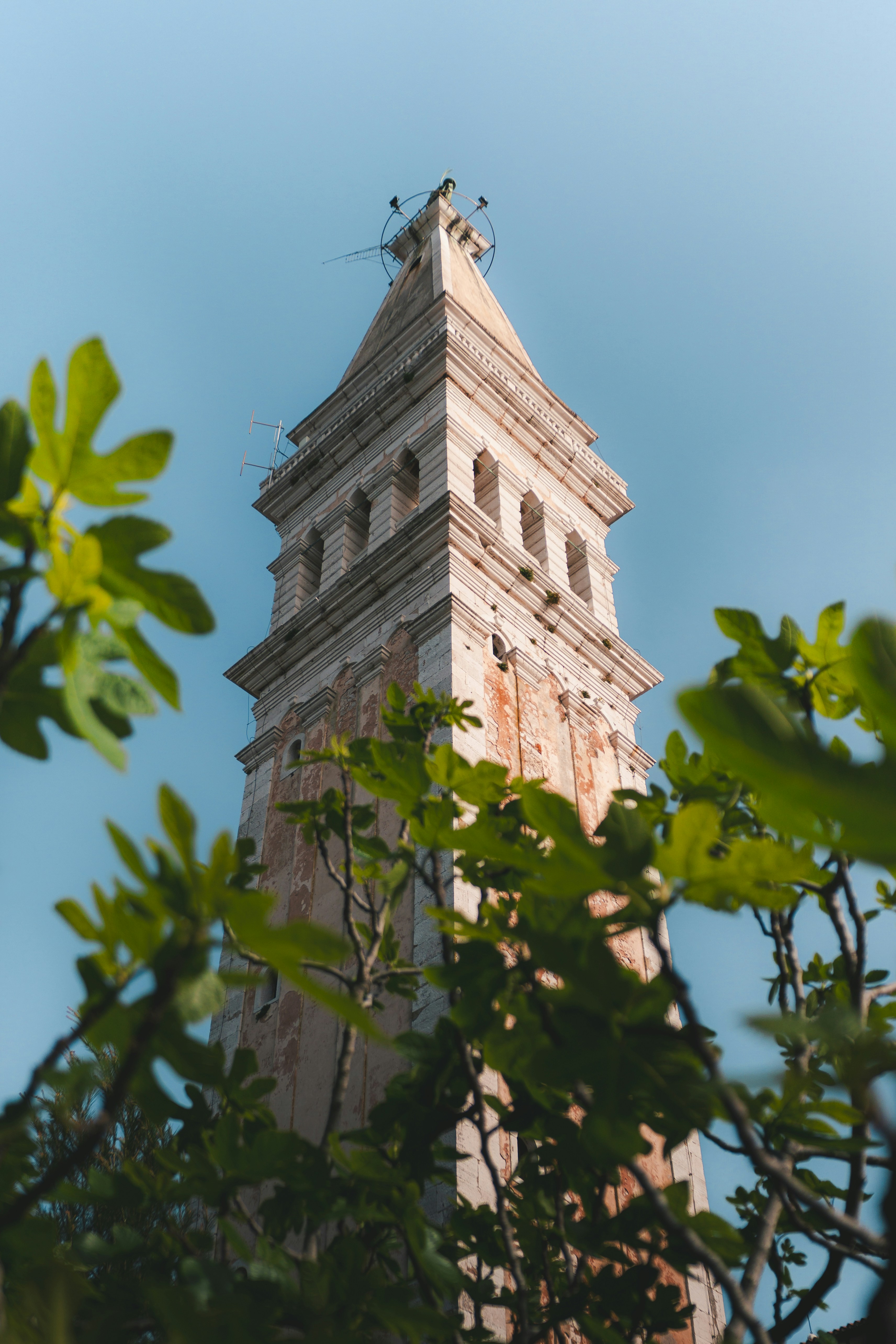 Old stone tower framed by green leaves against sky
