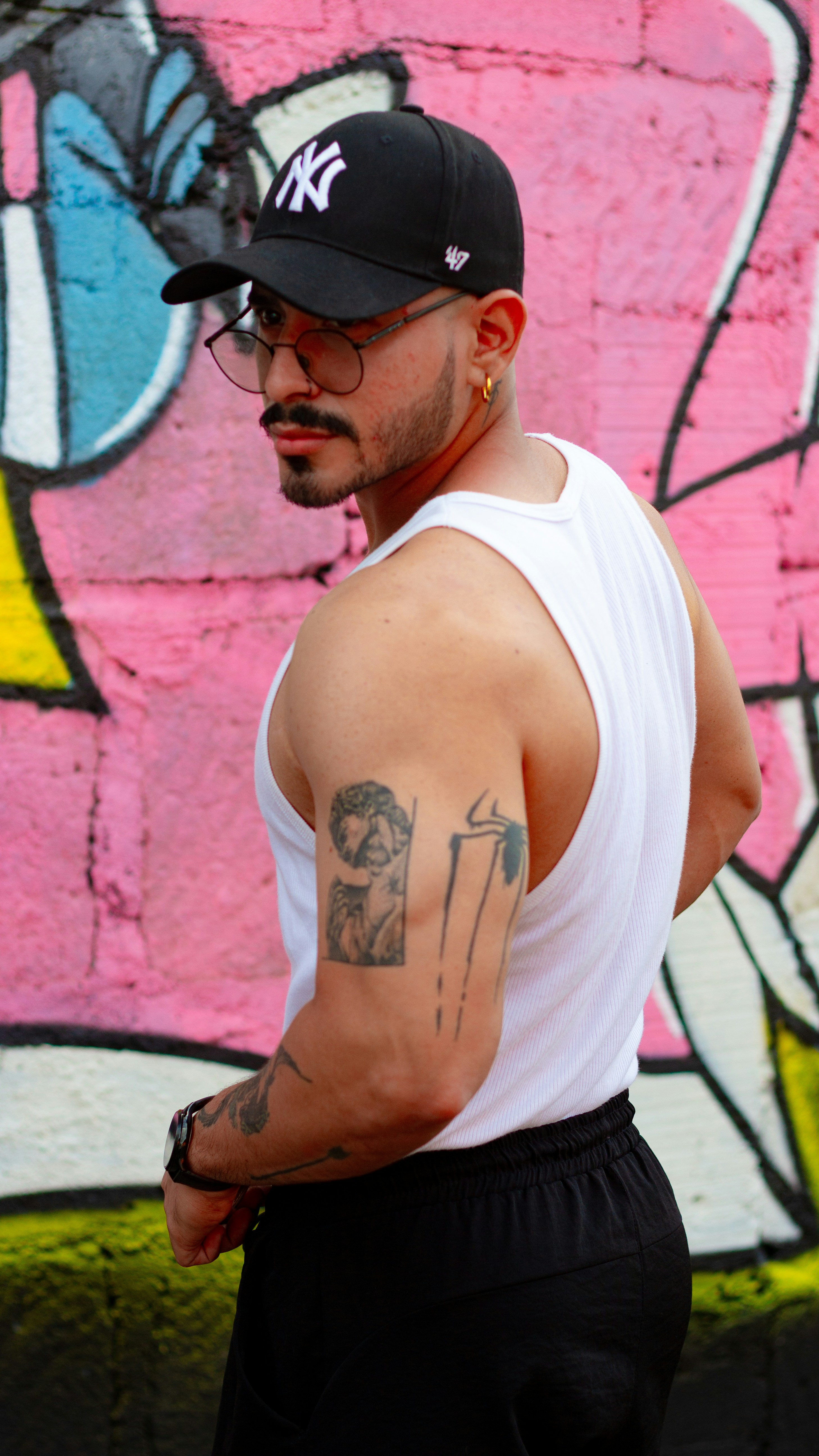 Graffiti Glow: Portrait of a Tattooed Man Standing Before a Pink Wall