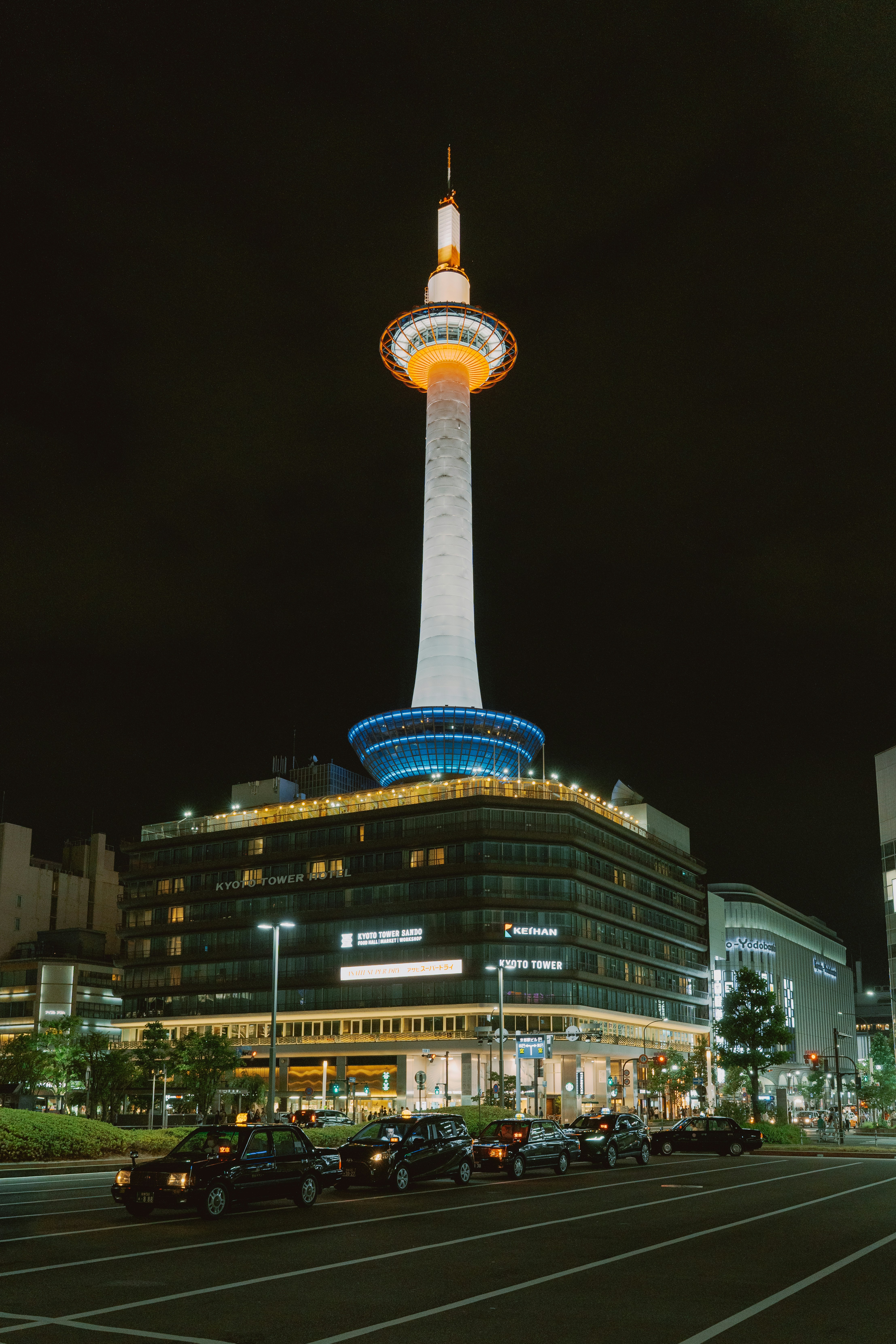 Kyoto tower illuminated at night with cars on street