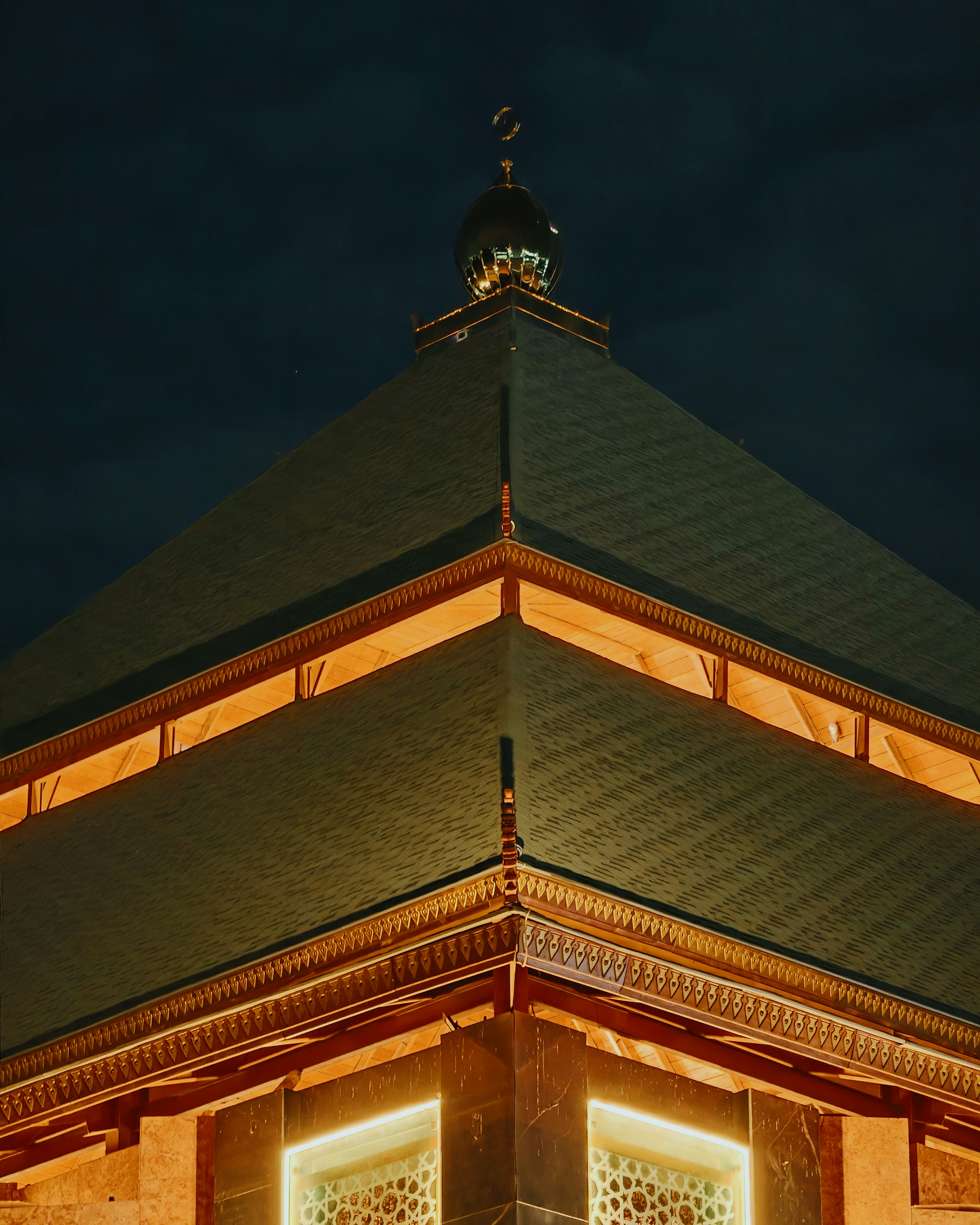 Mosque roof illuminated at night with crescent moon detail.