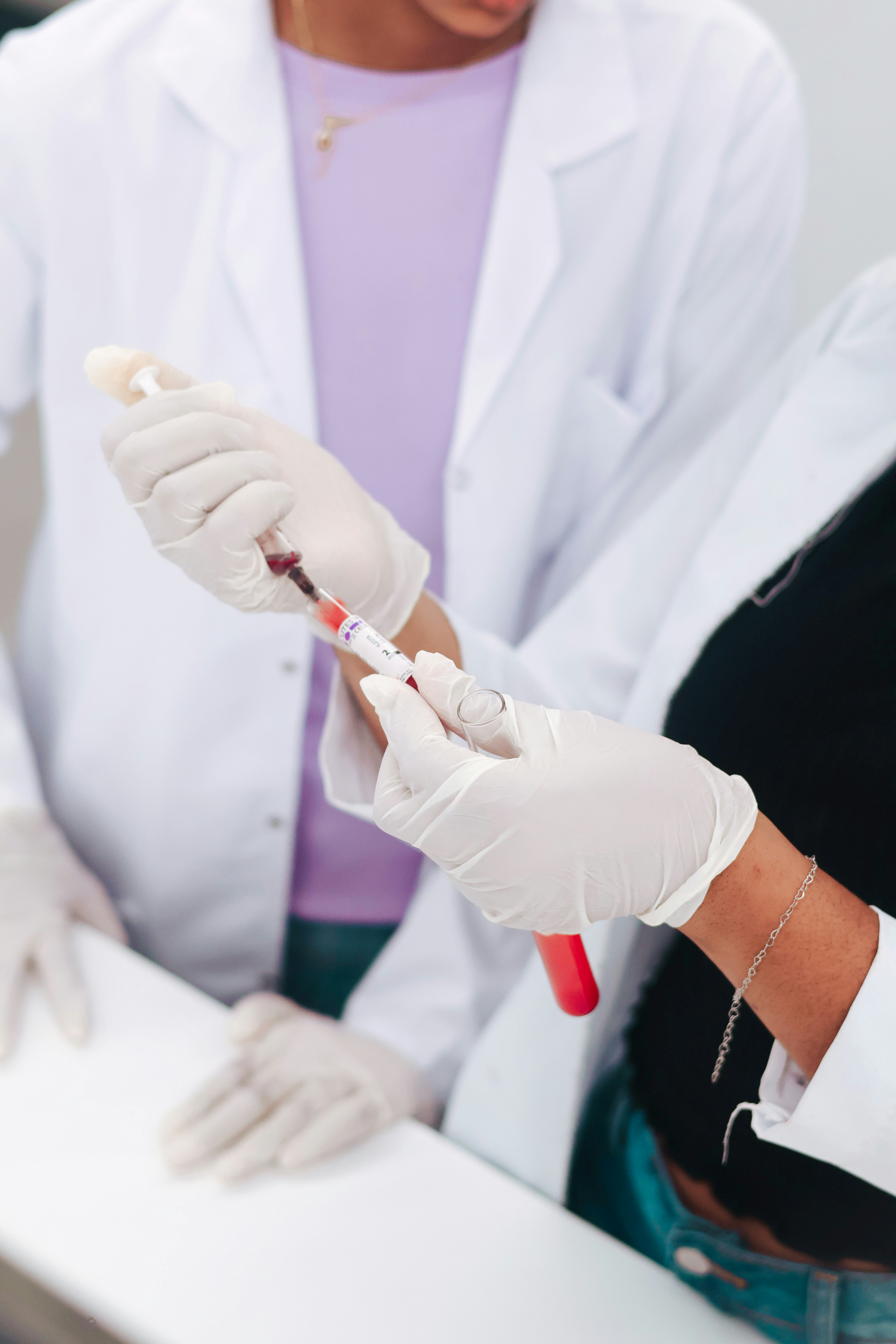 Two individuals in lab coats prepare a syringe for a medical procedure, showcasing the careful handling of medical instruments.
