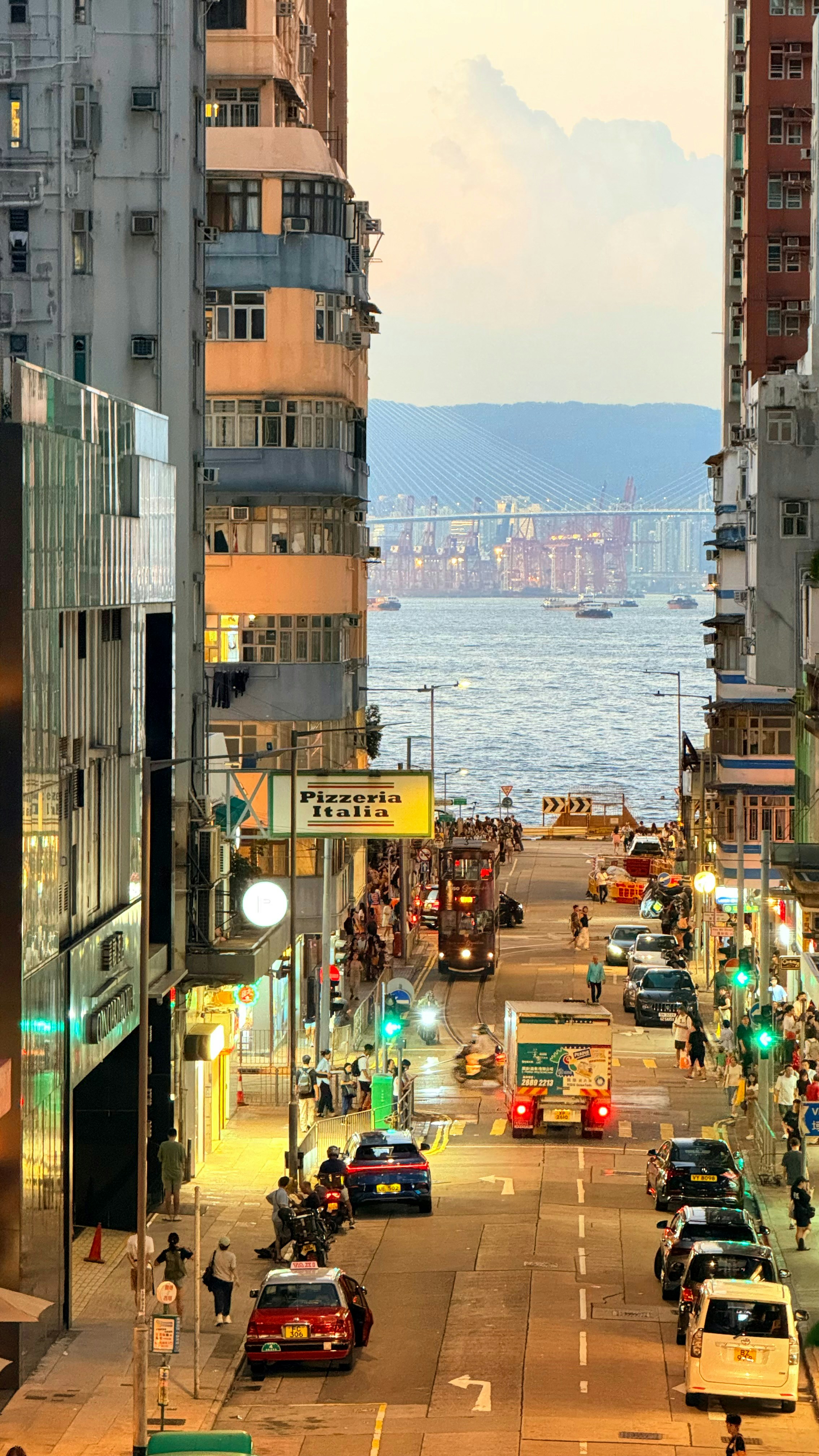 City street with traffic leading to the ocean at dusk.