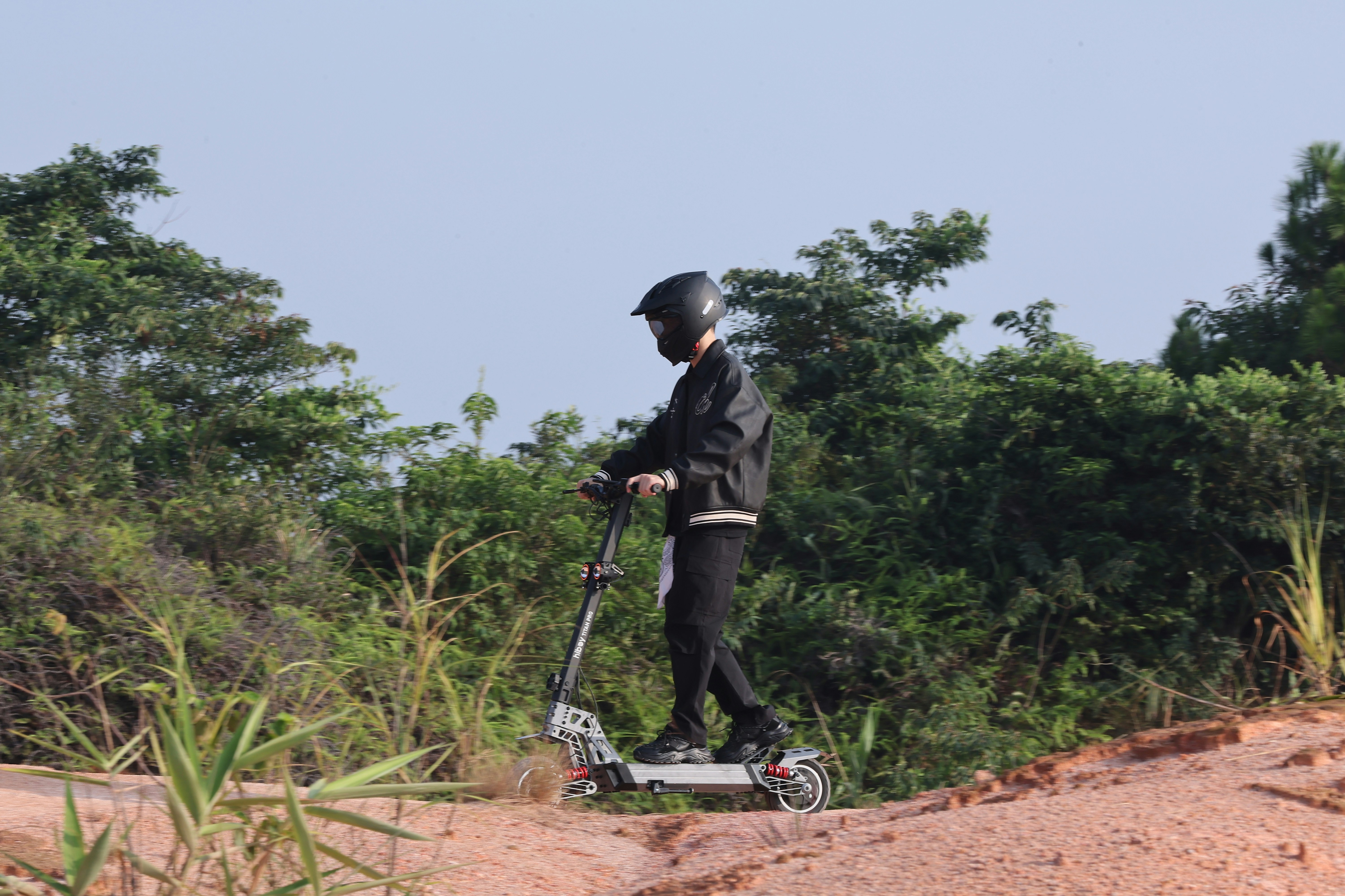 Dusty Ridge Ride: Black-Clad Rider on a Compact Electric Scooter