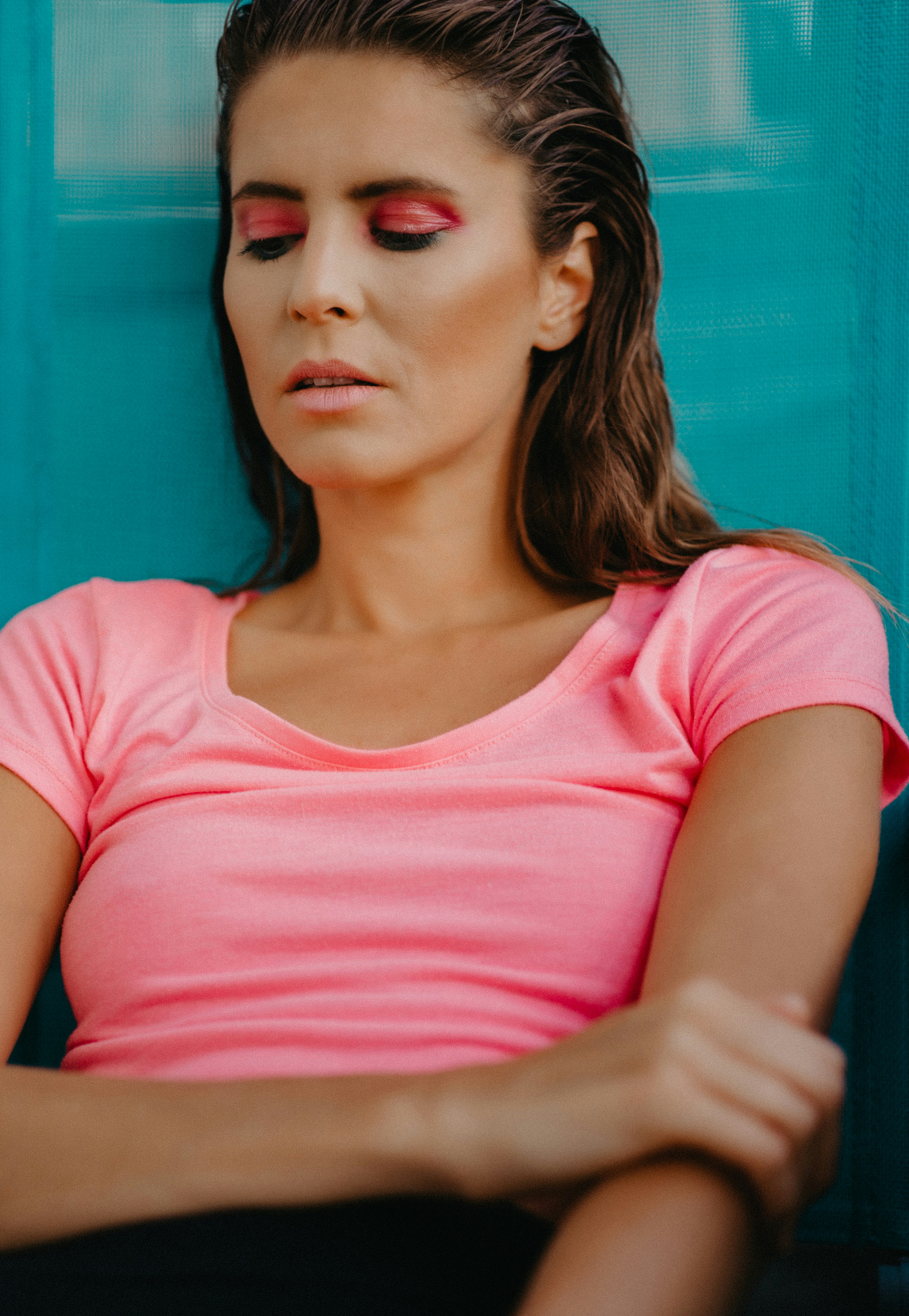 Woman with pink eyeshadow and pink shirt sits near blue