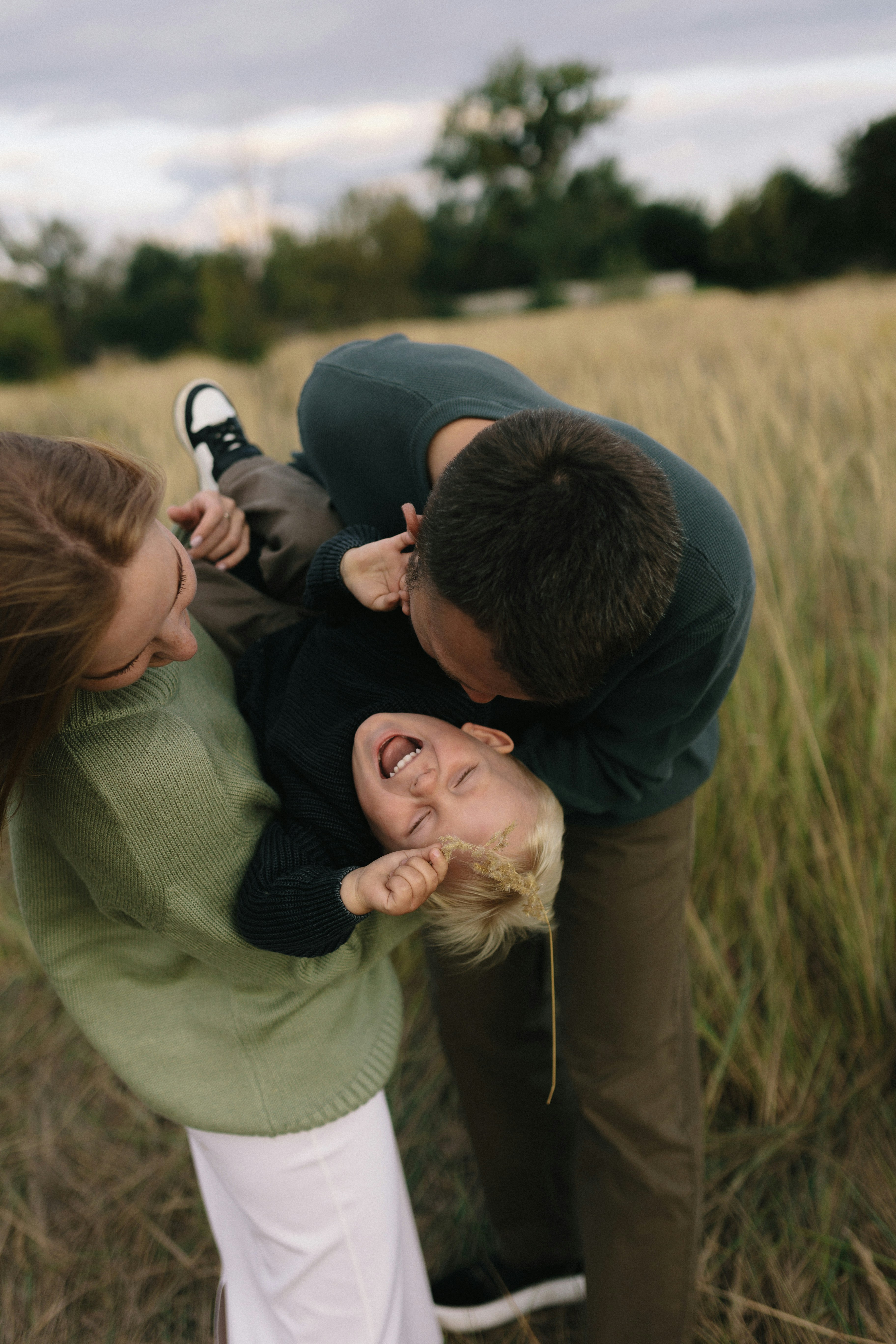 Family playing together in a grassy field.