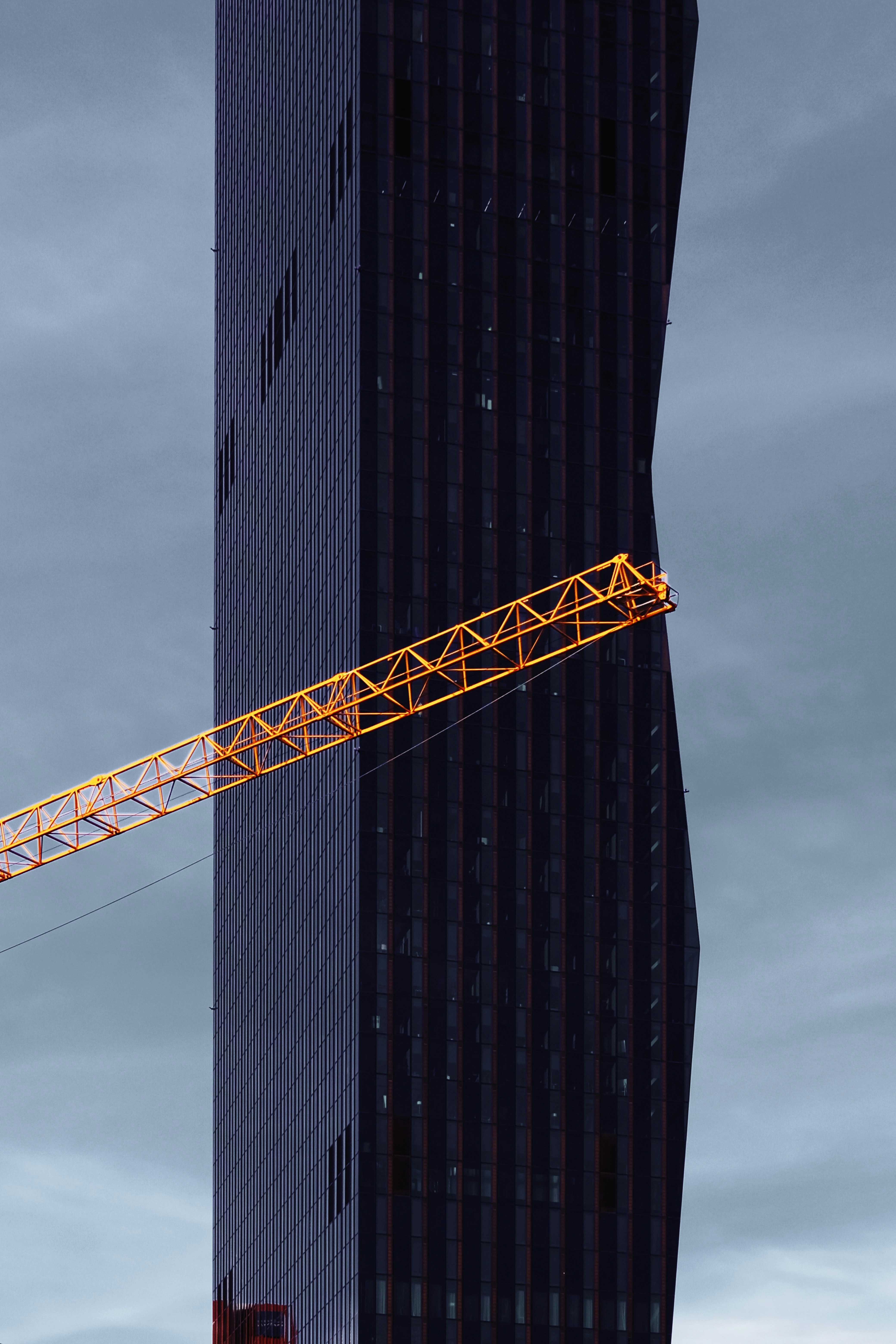 Tall dark skyscraper with a yellow construction crane.