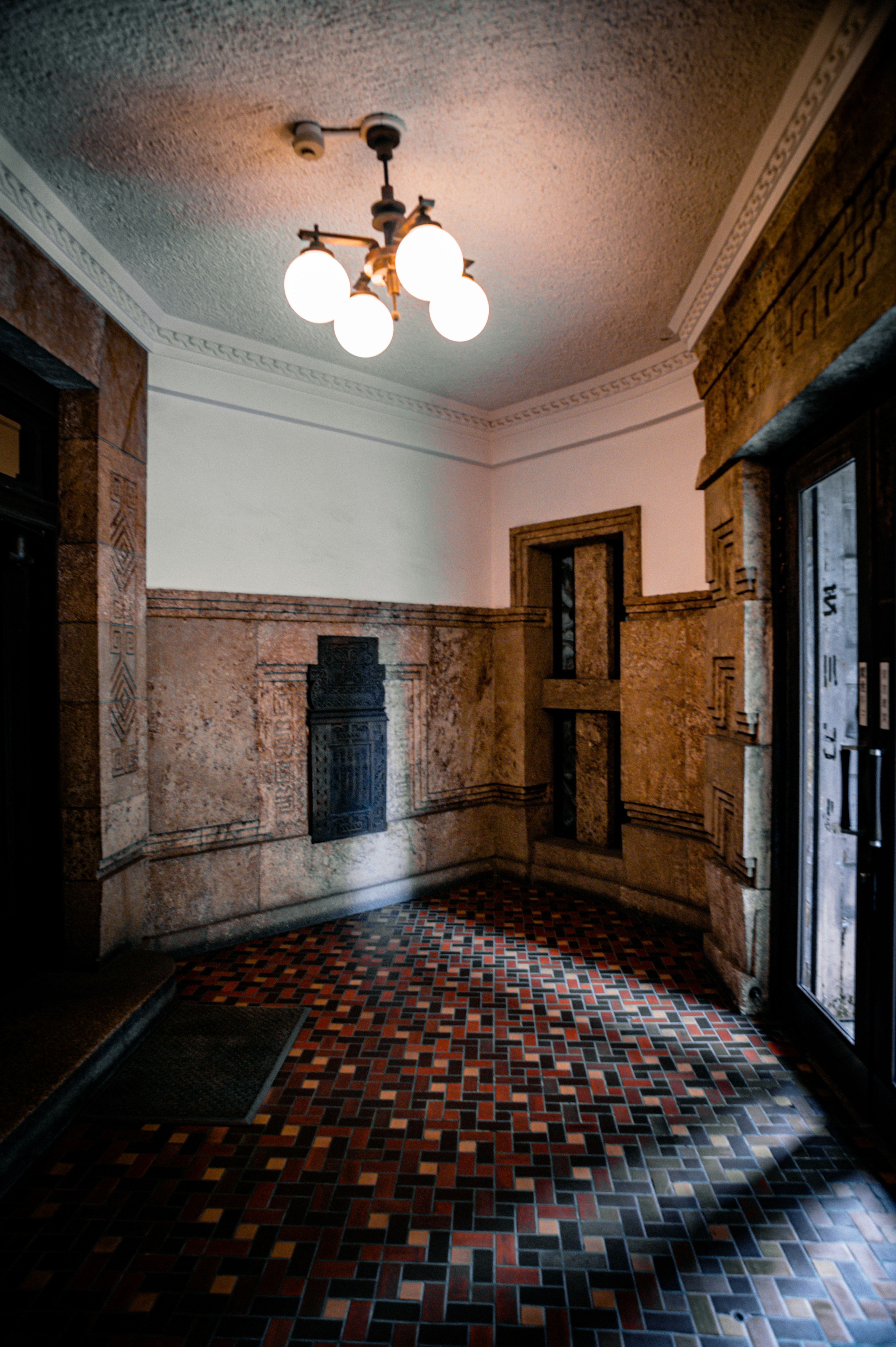 Ornate hallway with patterned tile floor and chandelier.