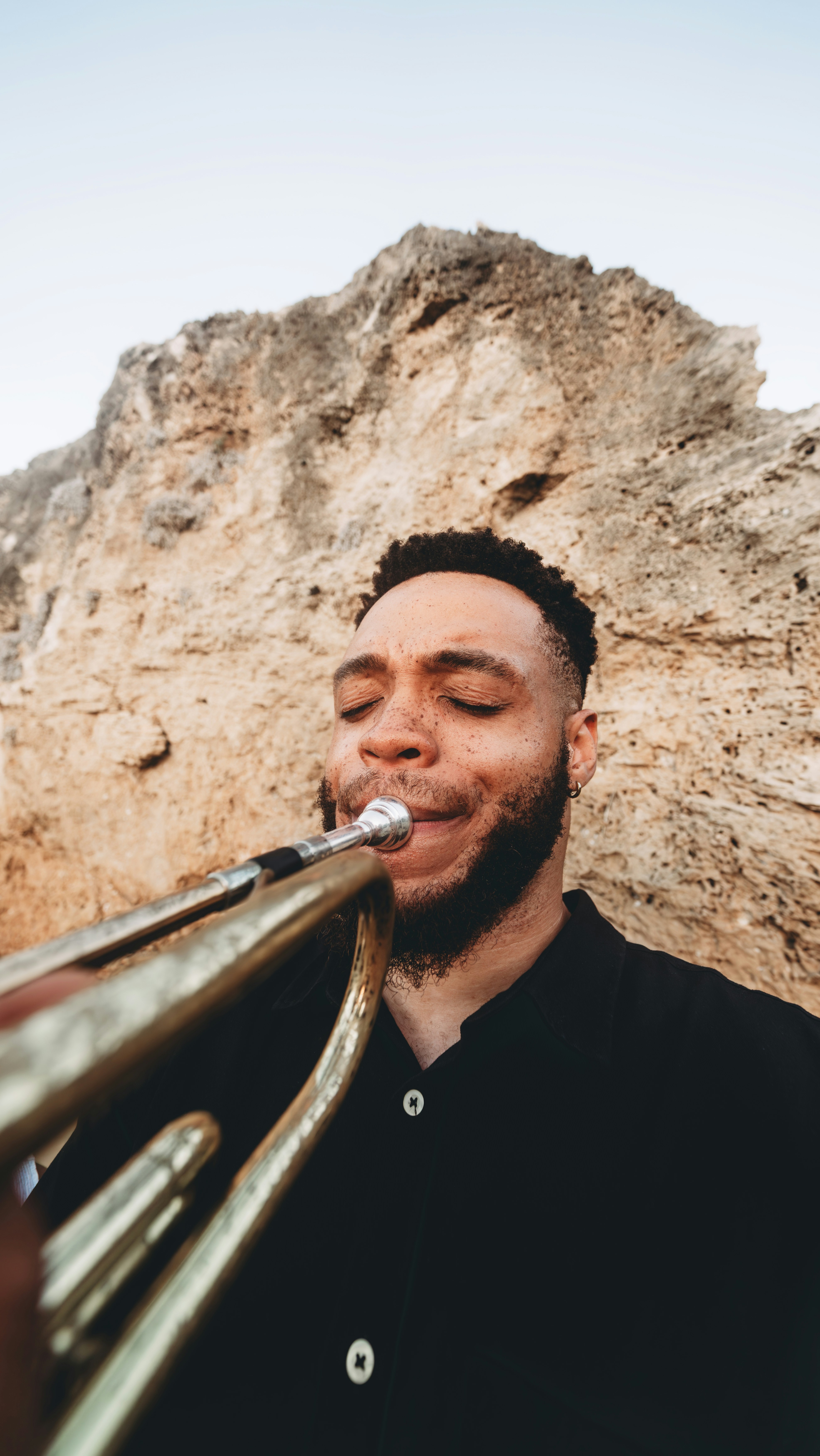 Man playing a trumpet near a rock formation photo – Free Portrait Image ...