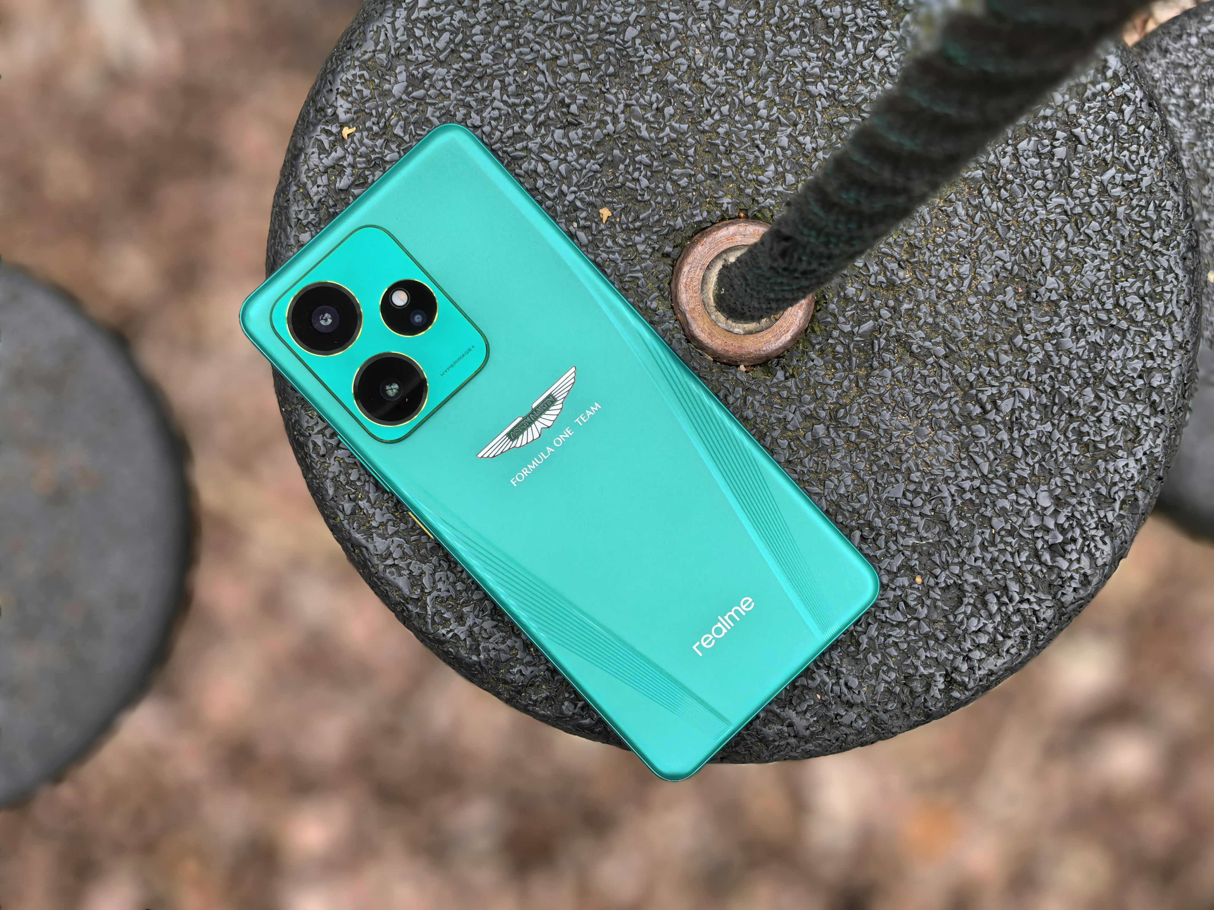 A teal smartphone resting on a textured surface.