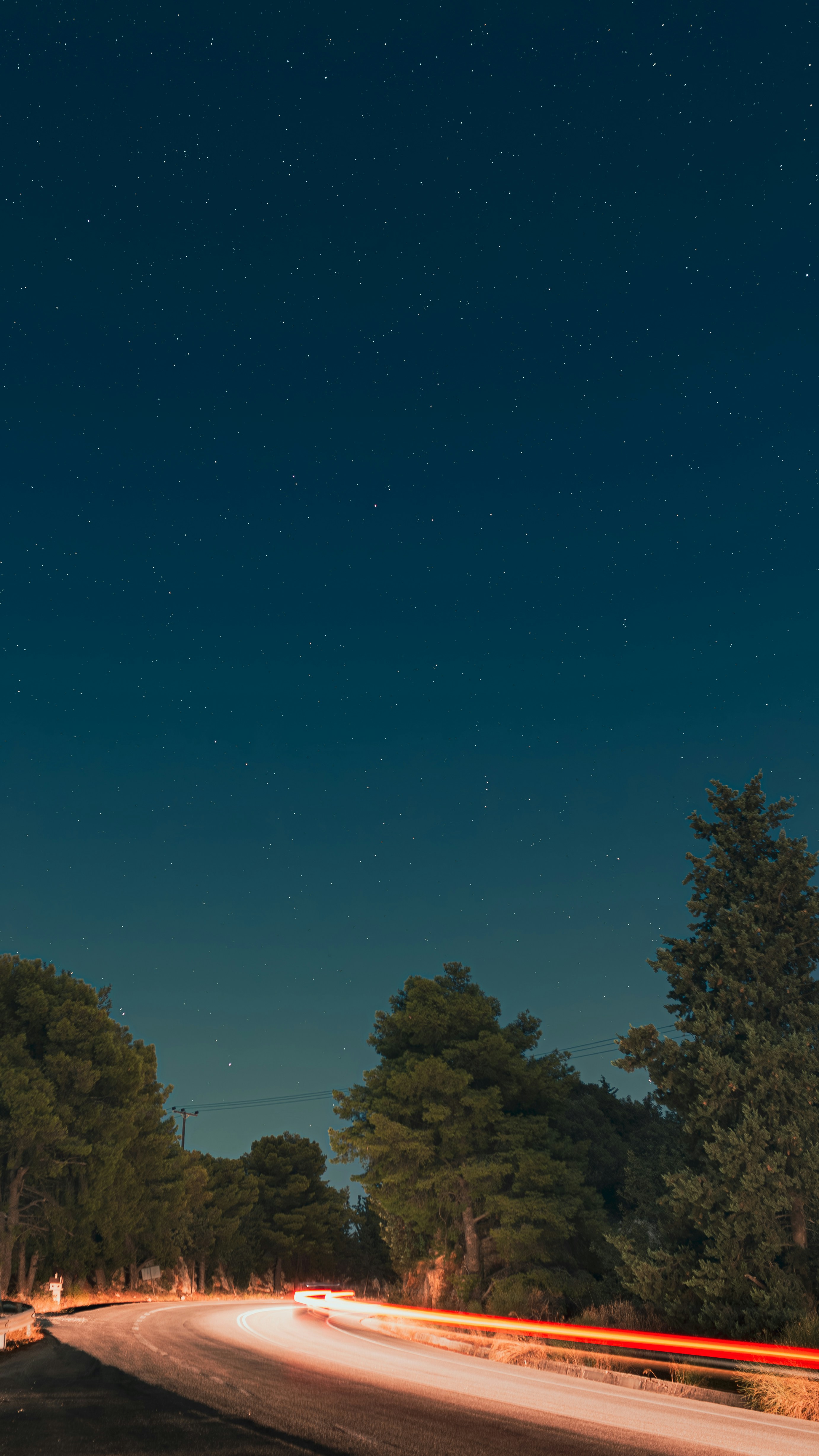 Road with light trails under a starry night sky.