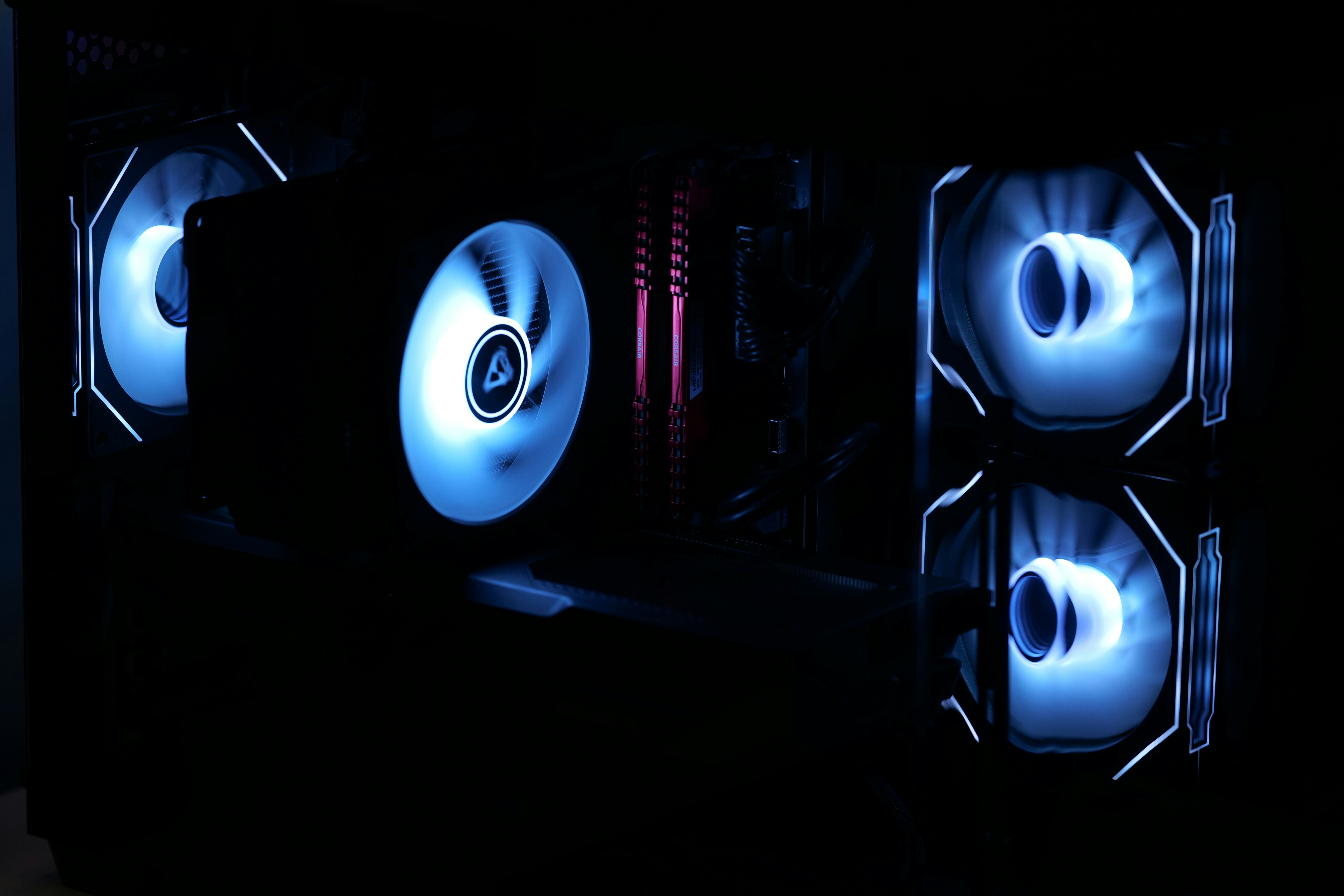 A close-up view of a gaming PC's cooling system, featuring vibrant blue LED fans and intricate components illuminated against a dark backdrop.