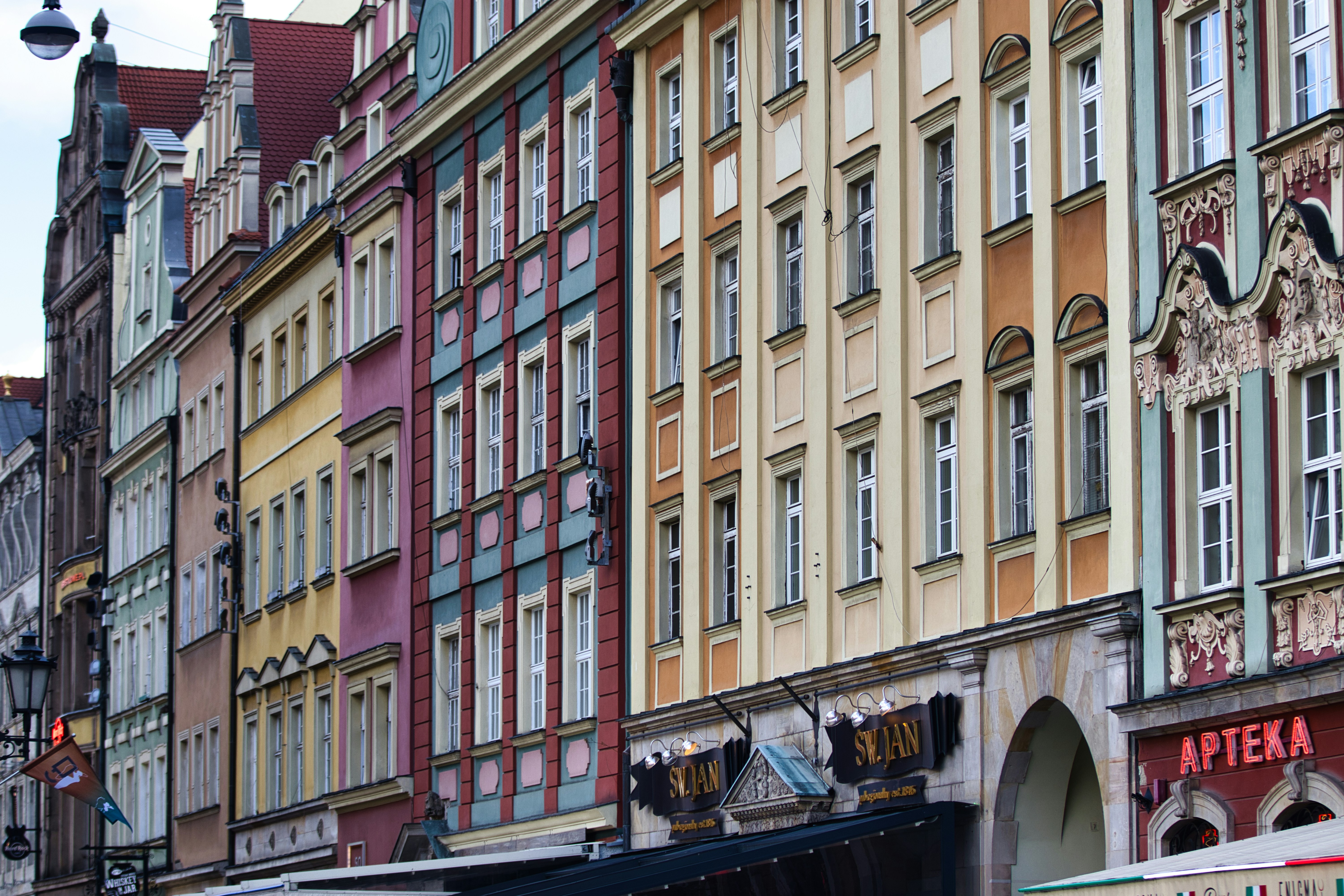 Vibrant row of historic buildings showcasing a blend of architectural styles and colors, with shops at street level. The scene captures the essence of urban charm.