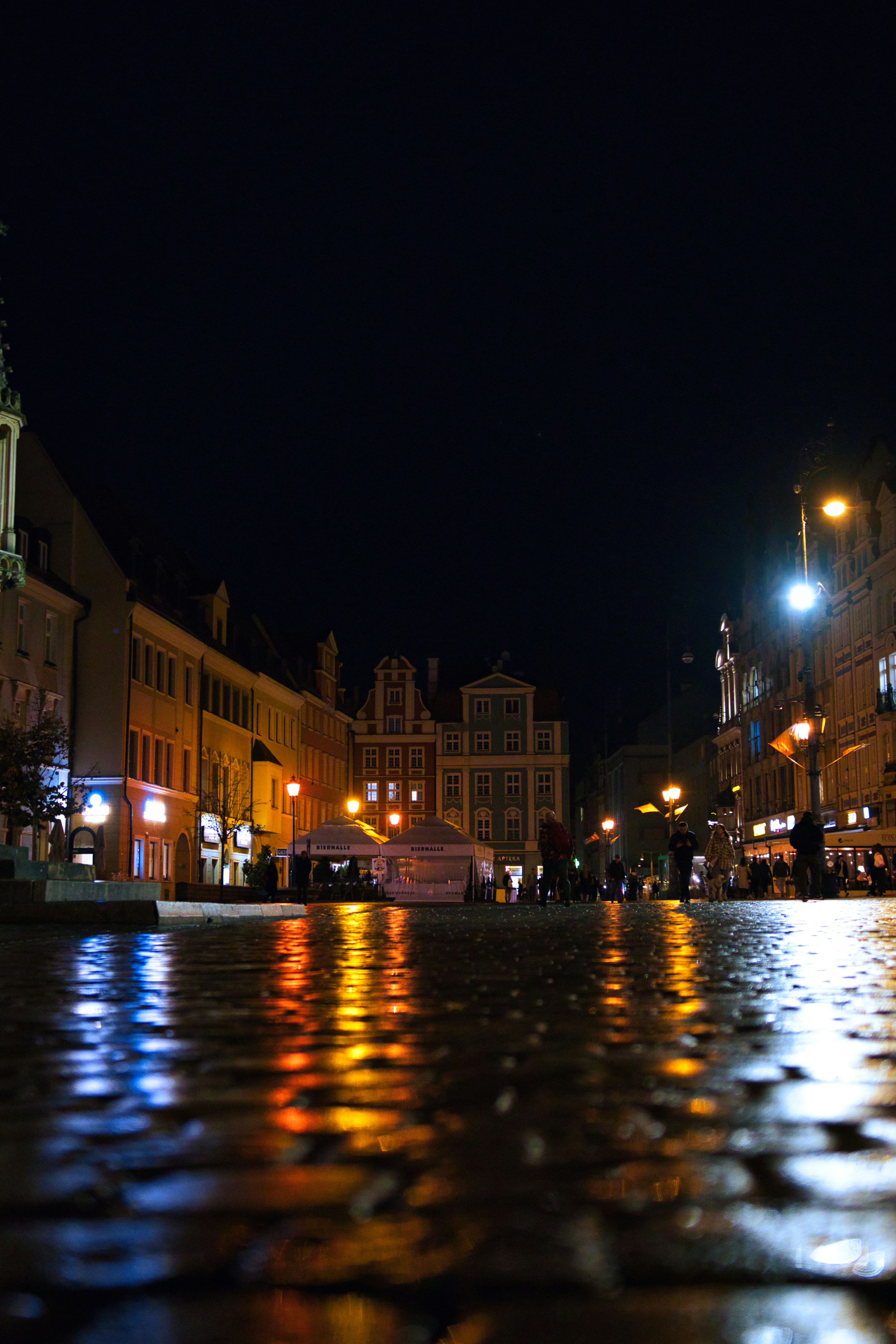 Wet cobblestone street reflecting city lights at night