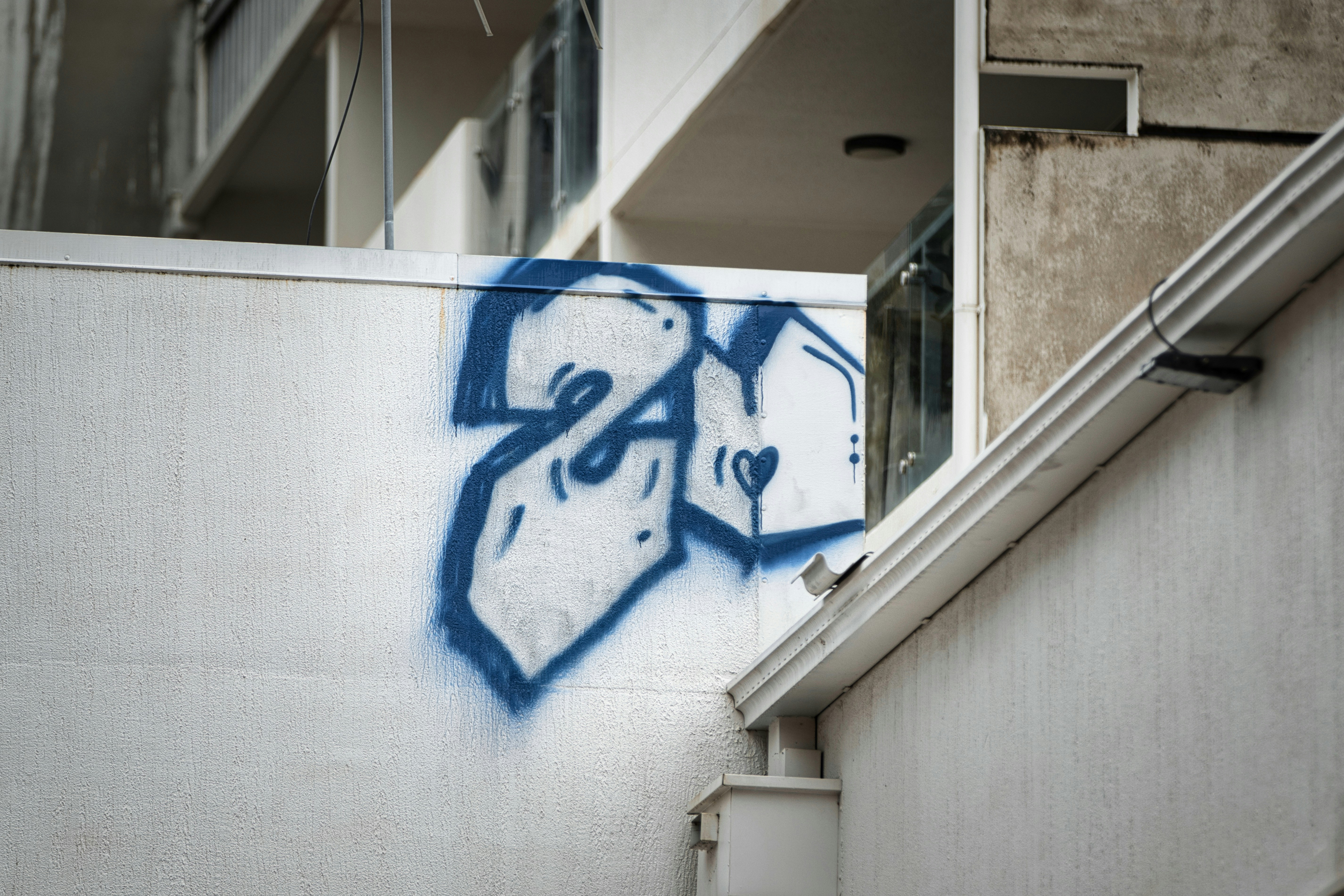 Graffiti art featuring stylized letters and a heart, painted on a white wall in an urban setting.