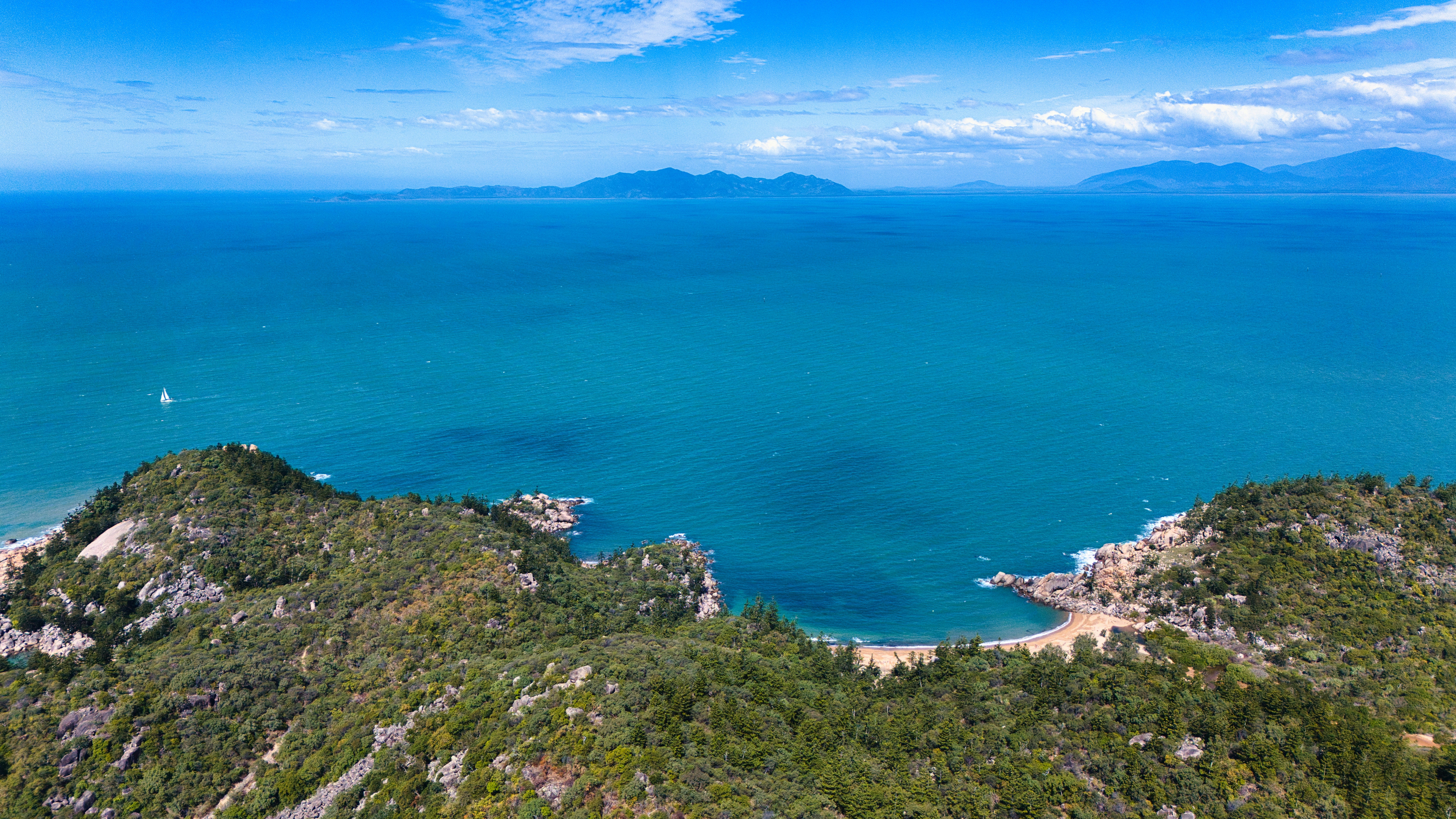 Lush green island coastline meets turquoise ocean waters.