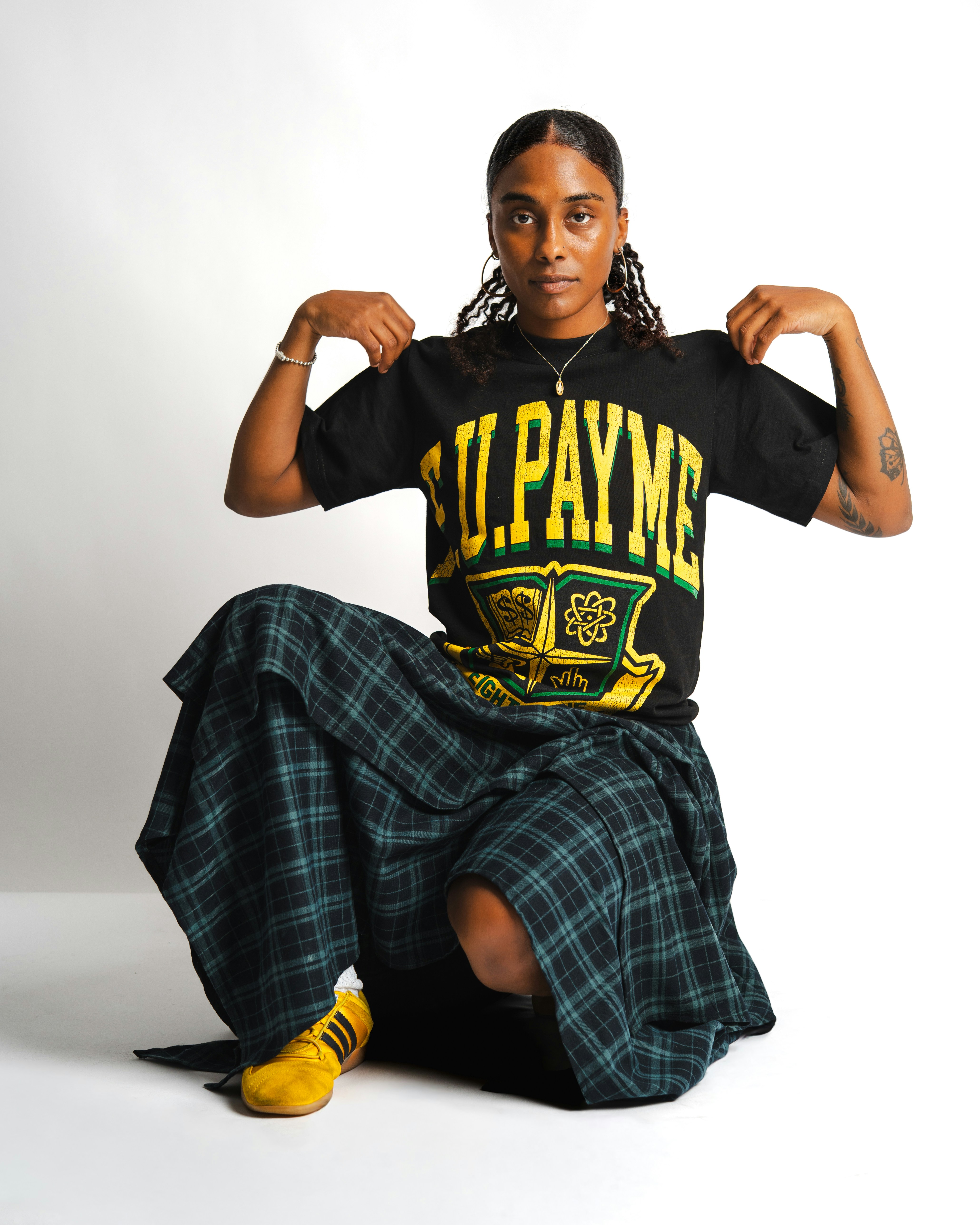Individual posing confidently in a graphic tee and plaid skirt, showcasing a unique blend of streetwear styles.