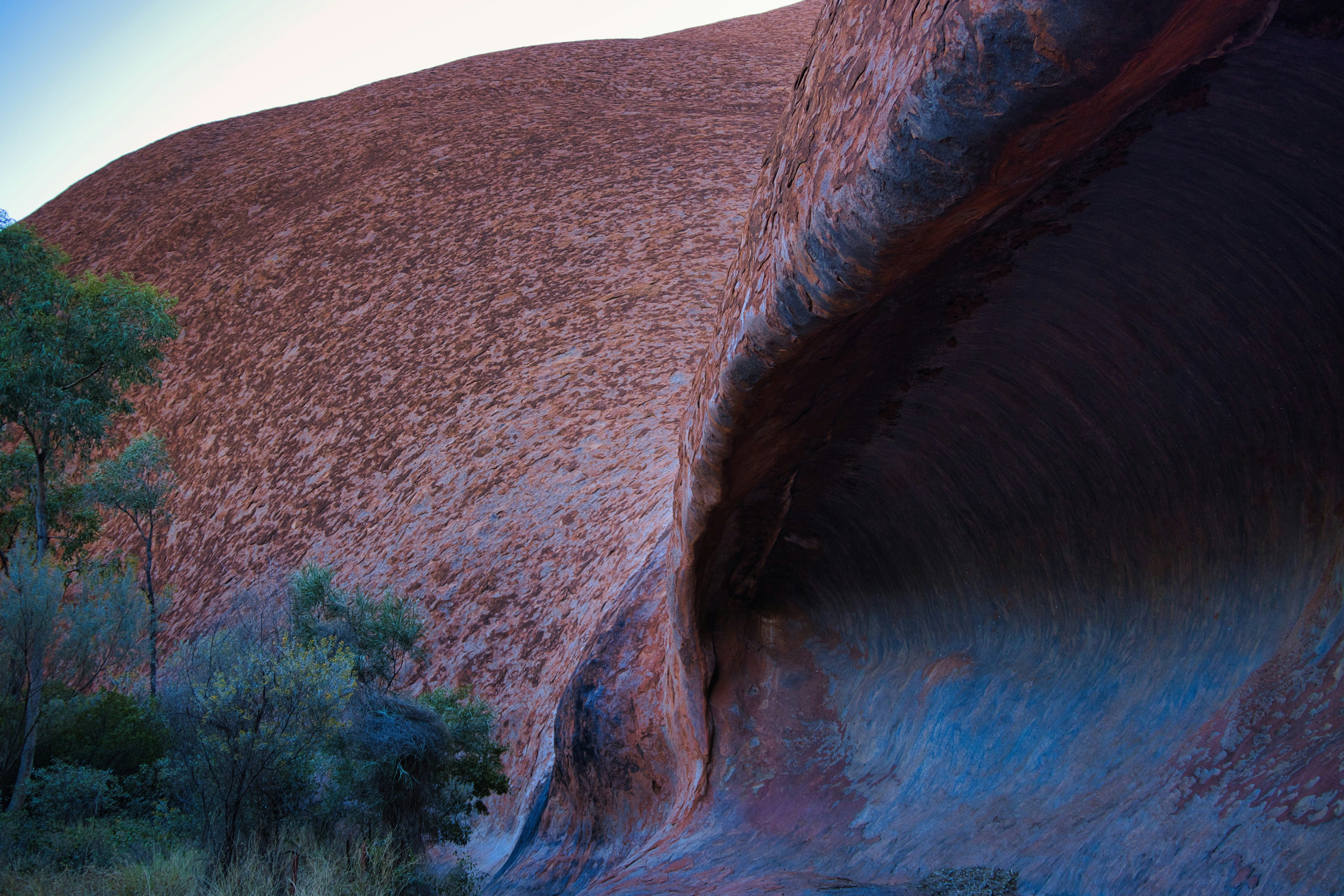 Giant sandstone monolith with vegetation at base.