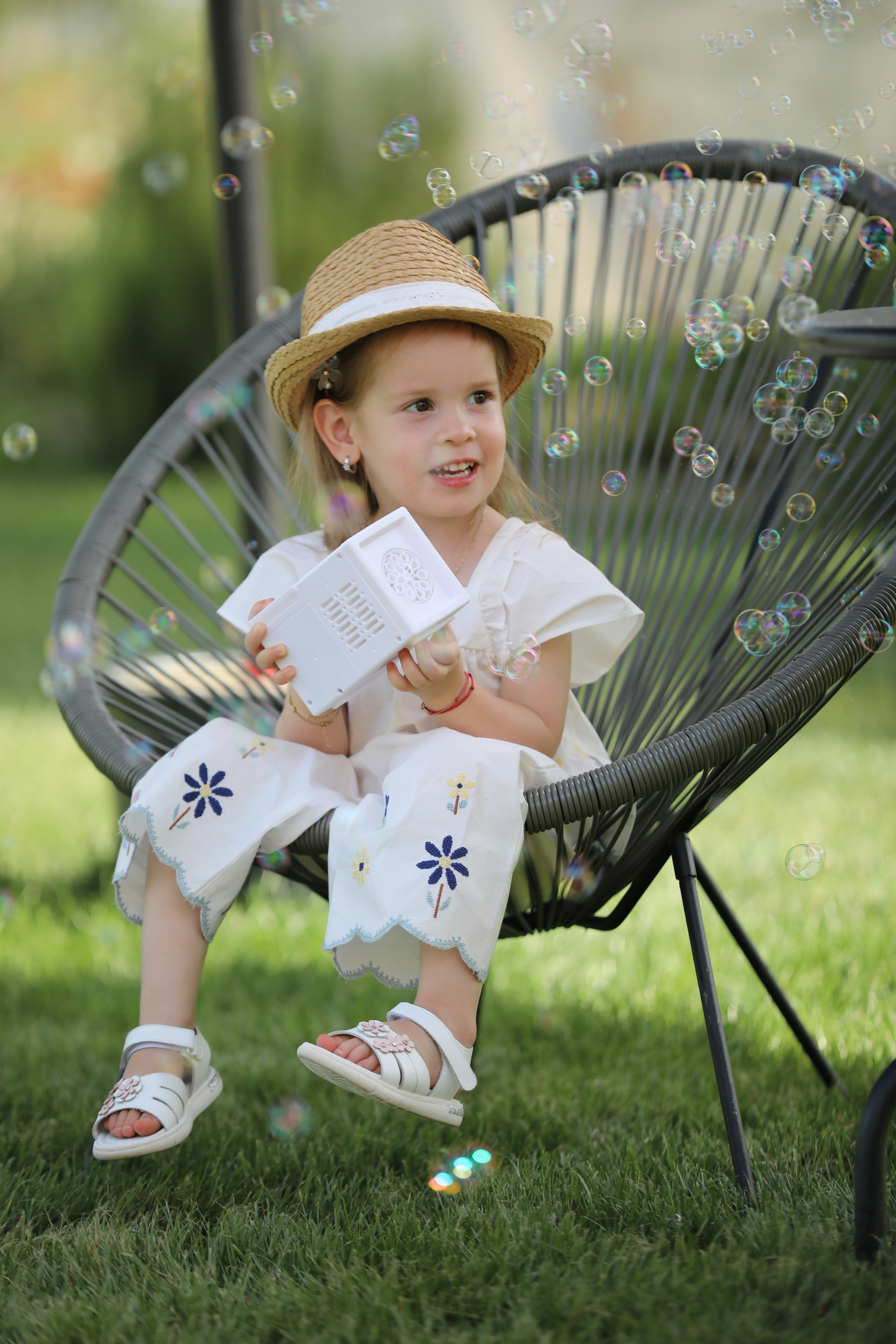 Young girl in hat sitting in chair with bubbles