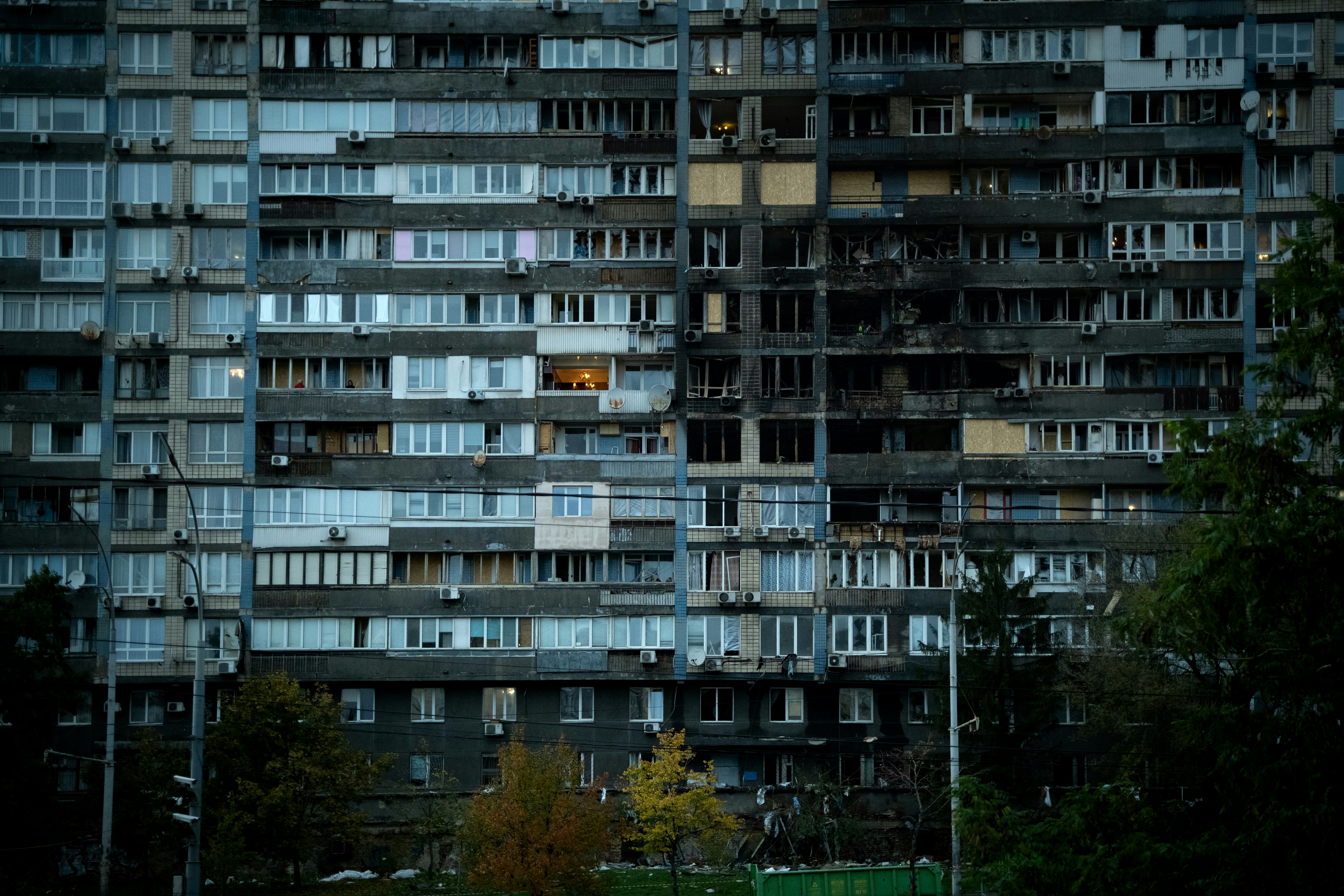 Dilapidated high-rise apartment building showcasing a mix of occupied and abandoned units, reflecting urban decay and resilience.