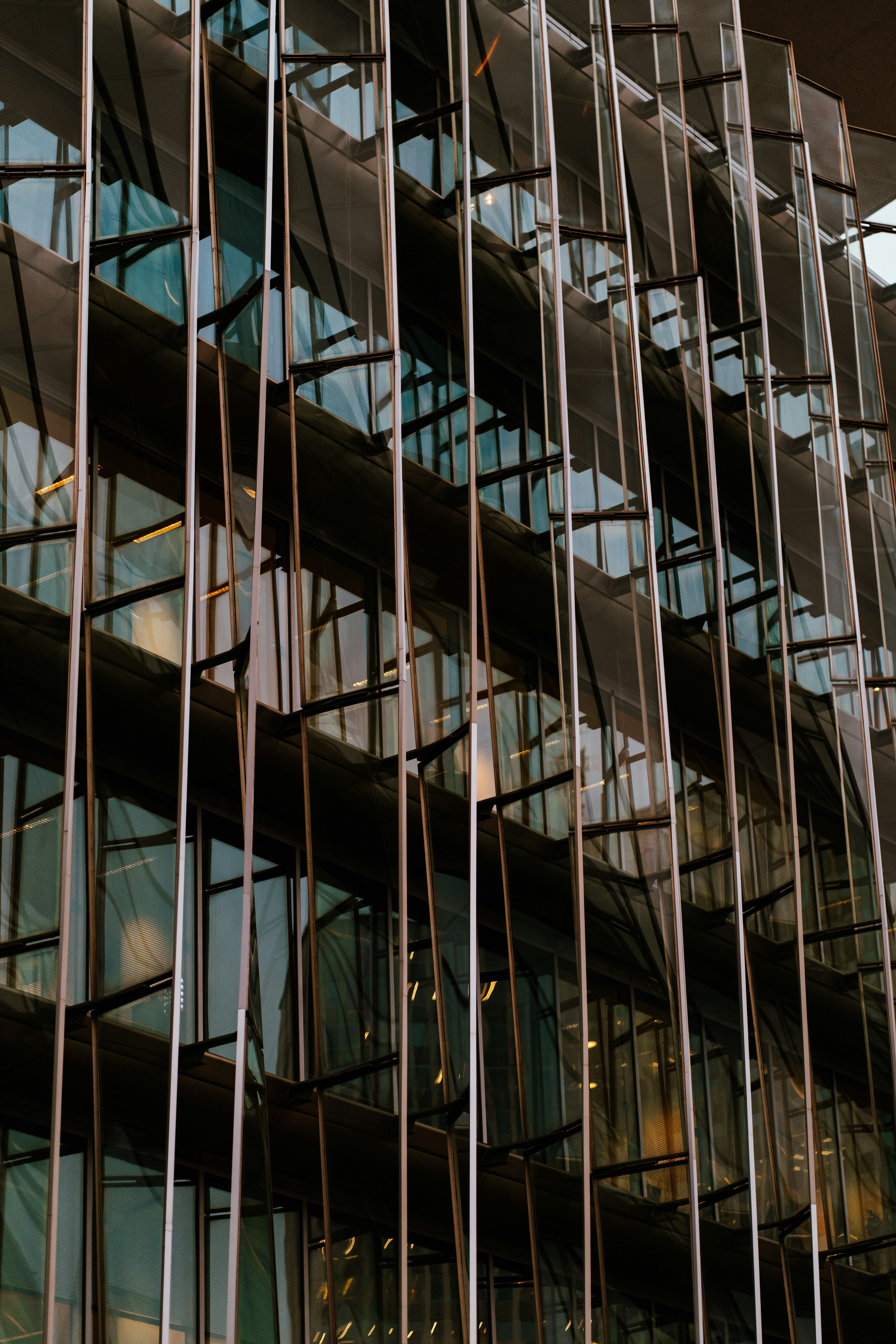 Abstract architectural facade showcasing a rhythmic pattern of glass and metal elements reflecting ambient light.
