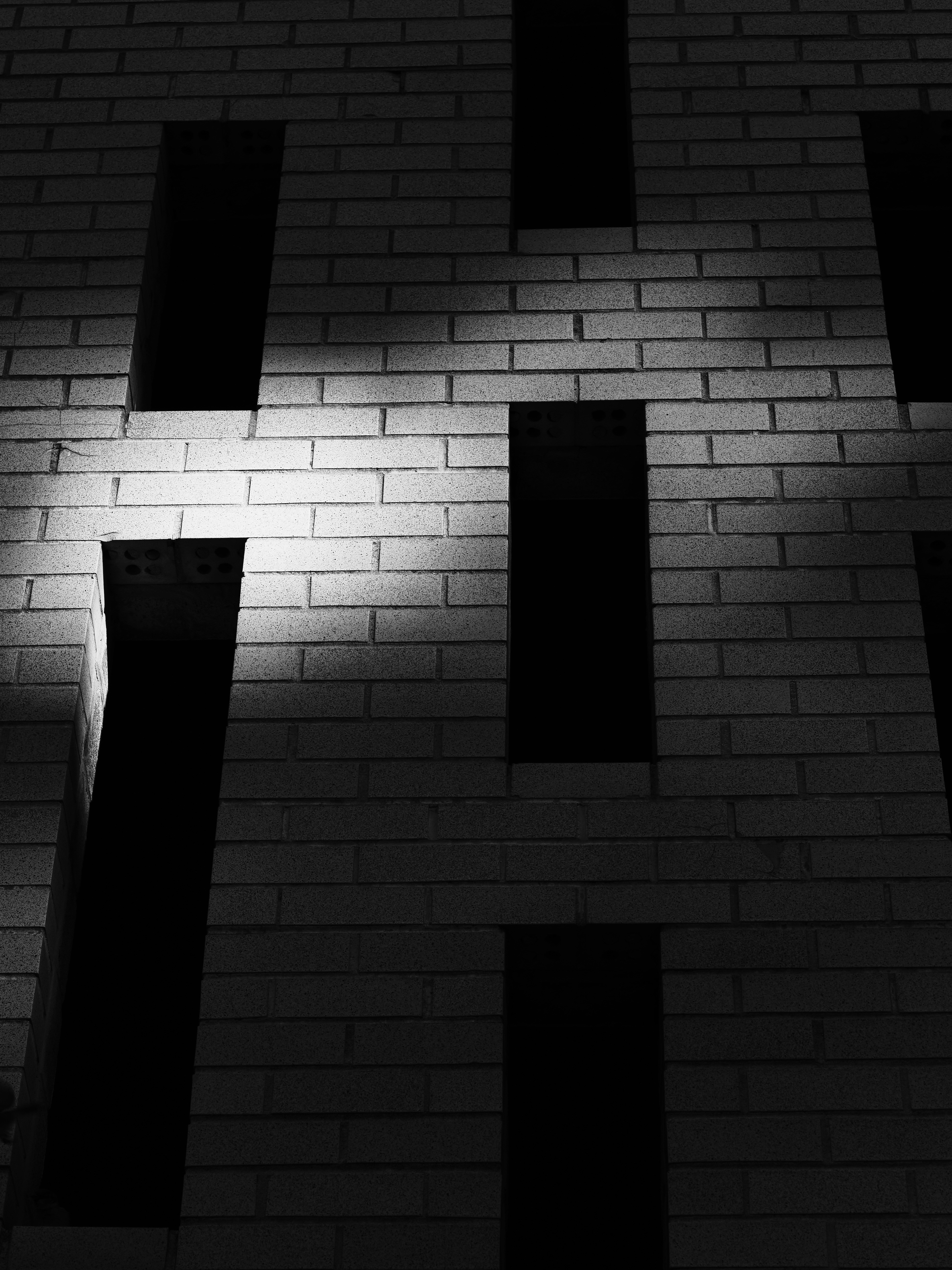 Light cascading over a textured brick wall, creating striking contrasts and geometric patterns.