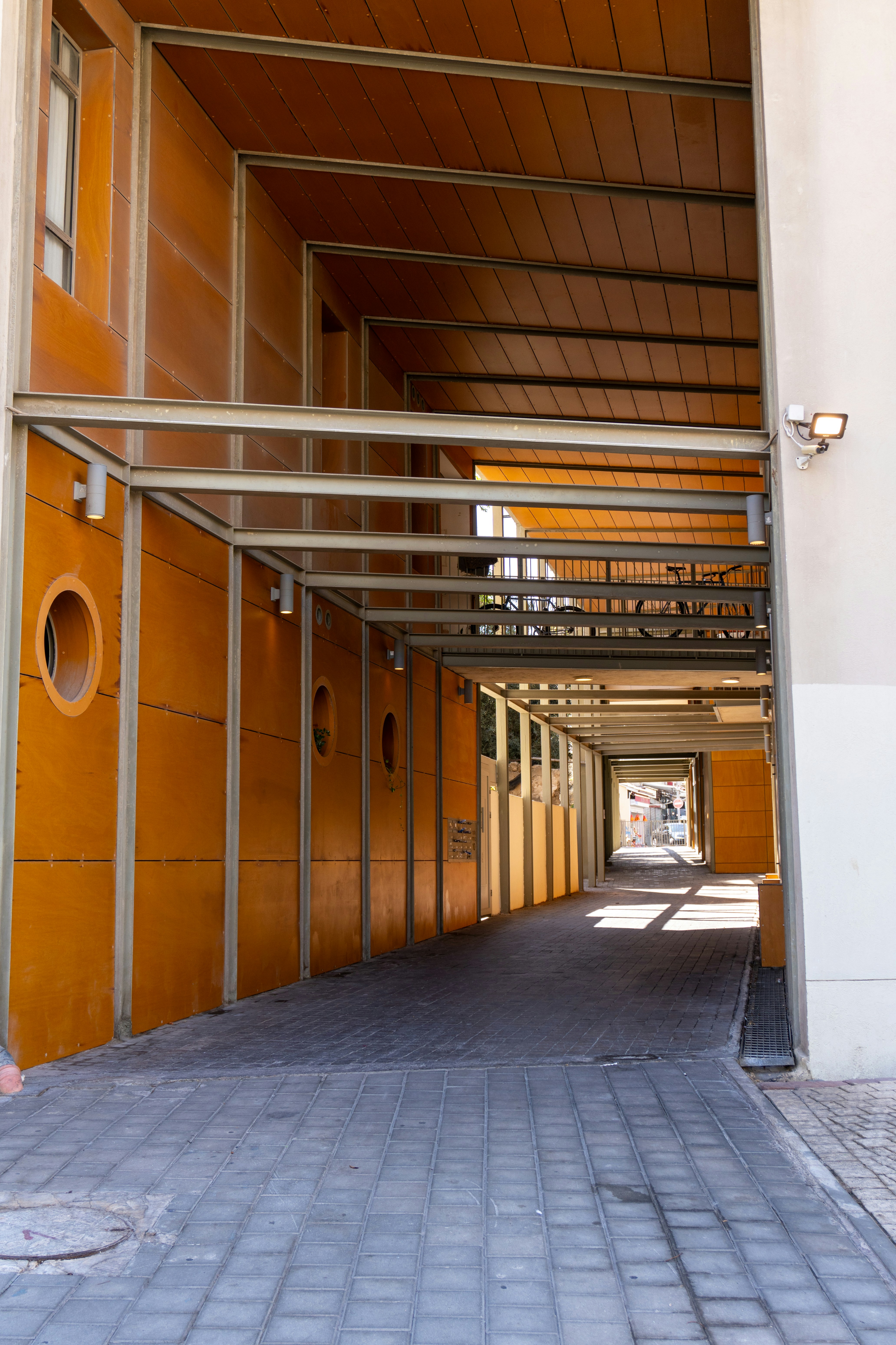 Vibrant orange walls frame a modern architectural corridor, leading to an inviting exit. The geometric lines create a dynamic visual experience.
