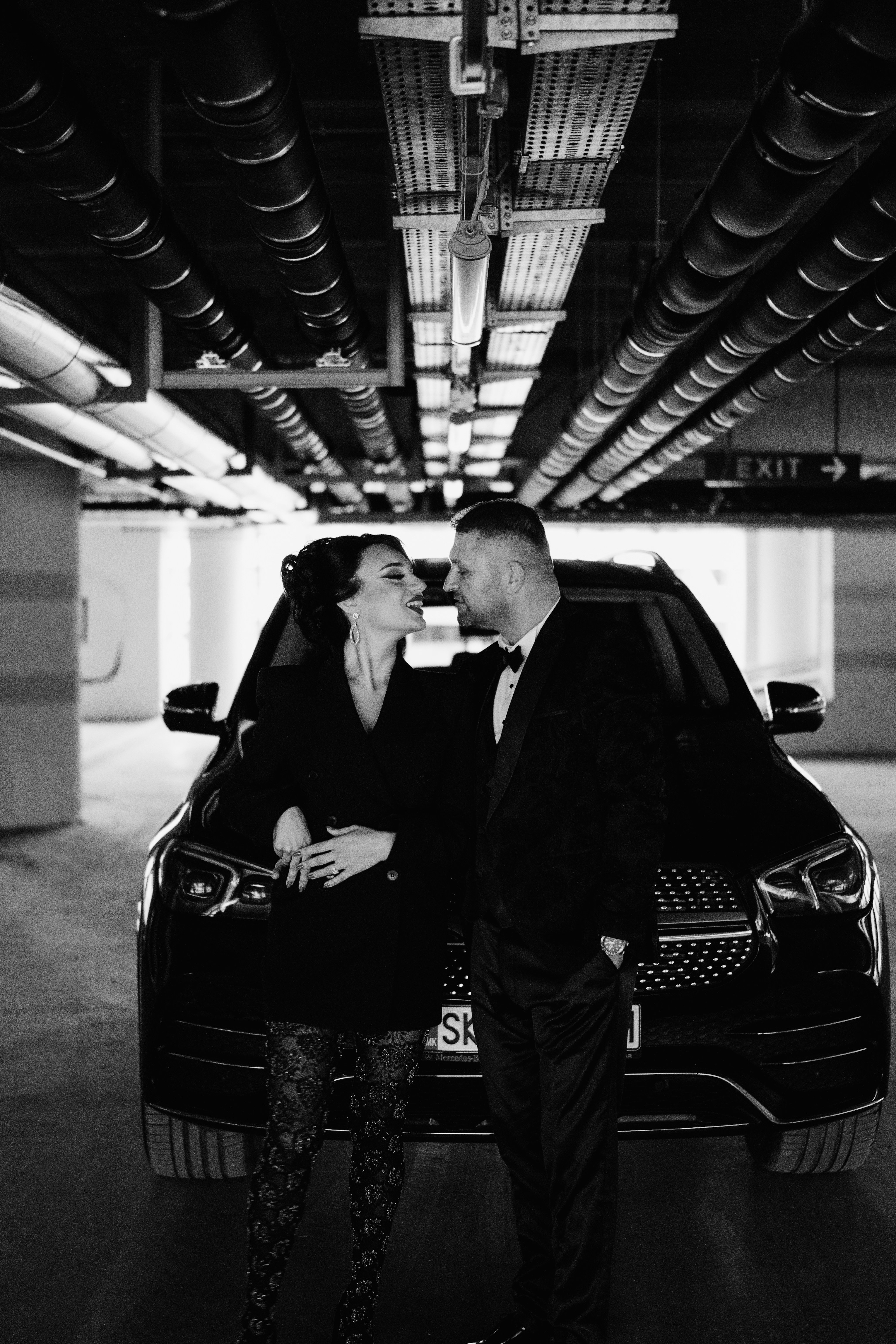 Midnight Dash: Couple Leaning Into Shared Laugh by a Sleek SUV