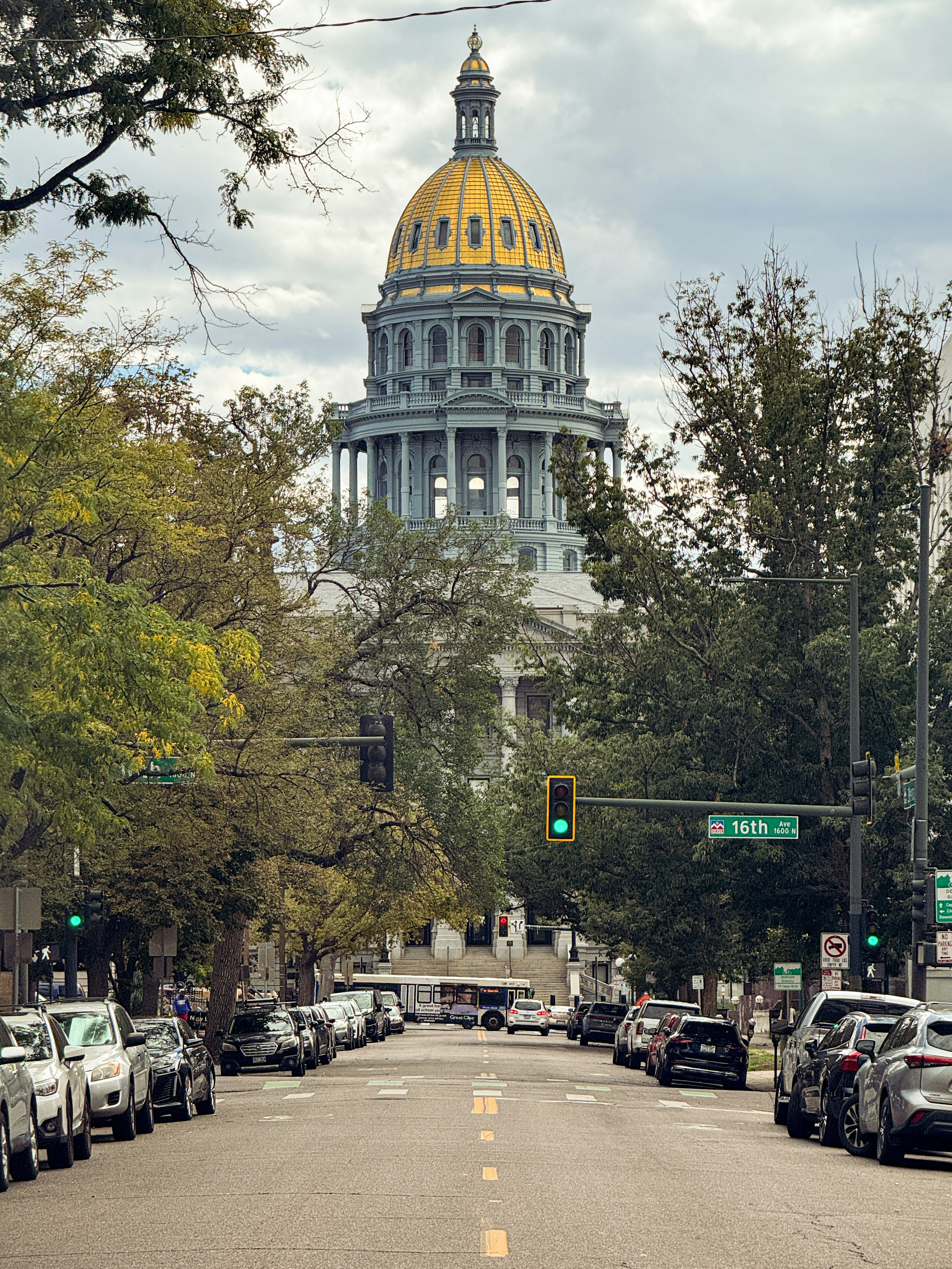 The iconic golden dome of a historic building rises above tree-lined streets, framed by a bustling urban landscape.