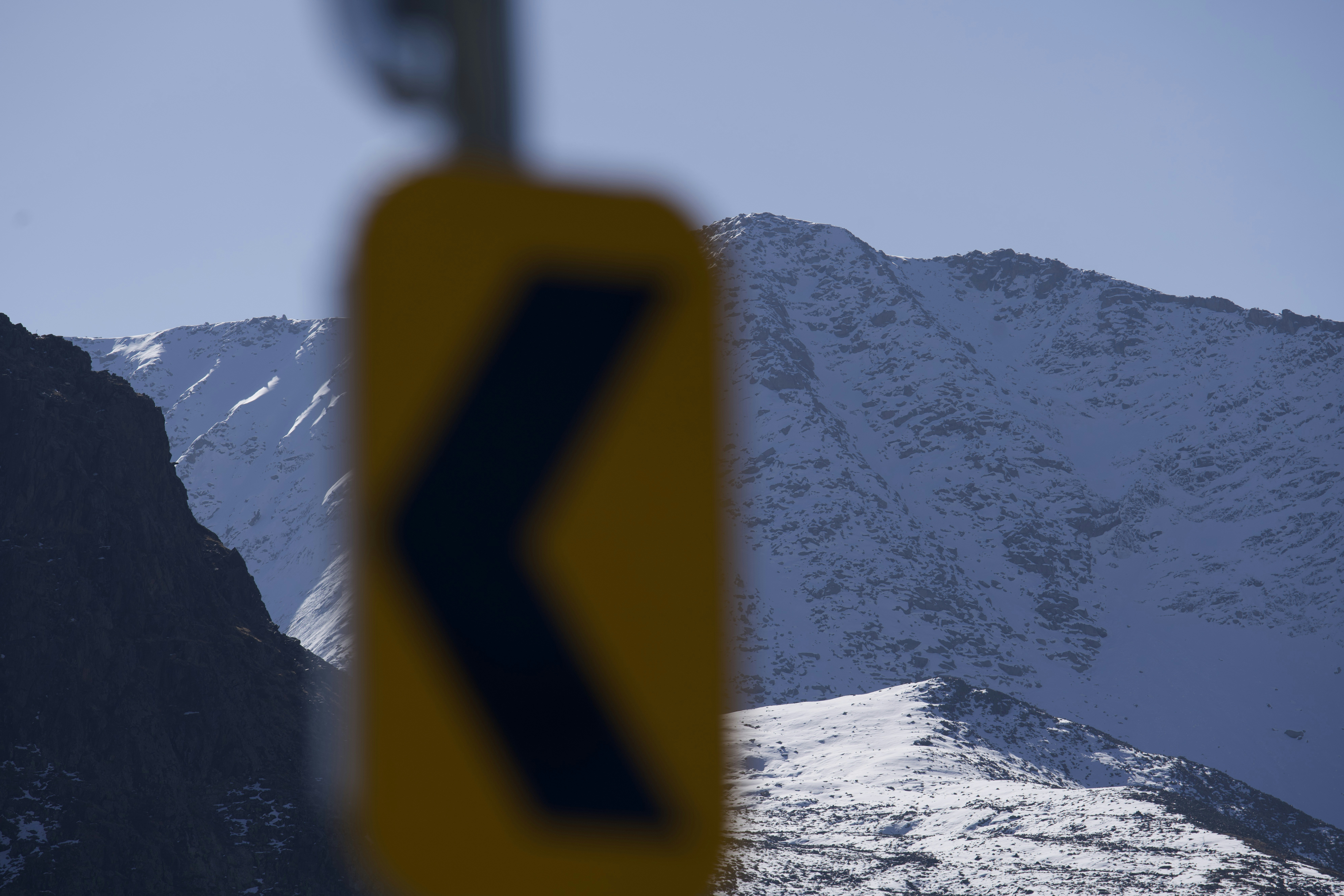 Blurry Foreground Sign Framing a Snowbound Alpine Ridge