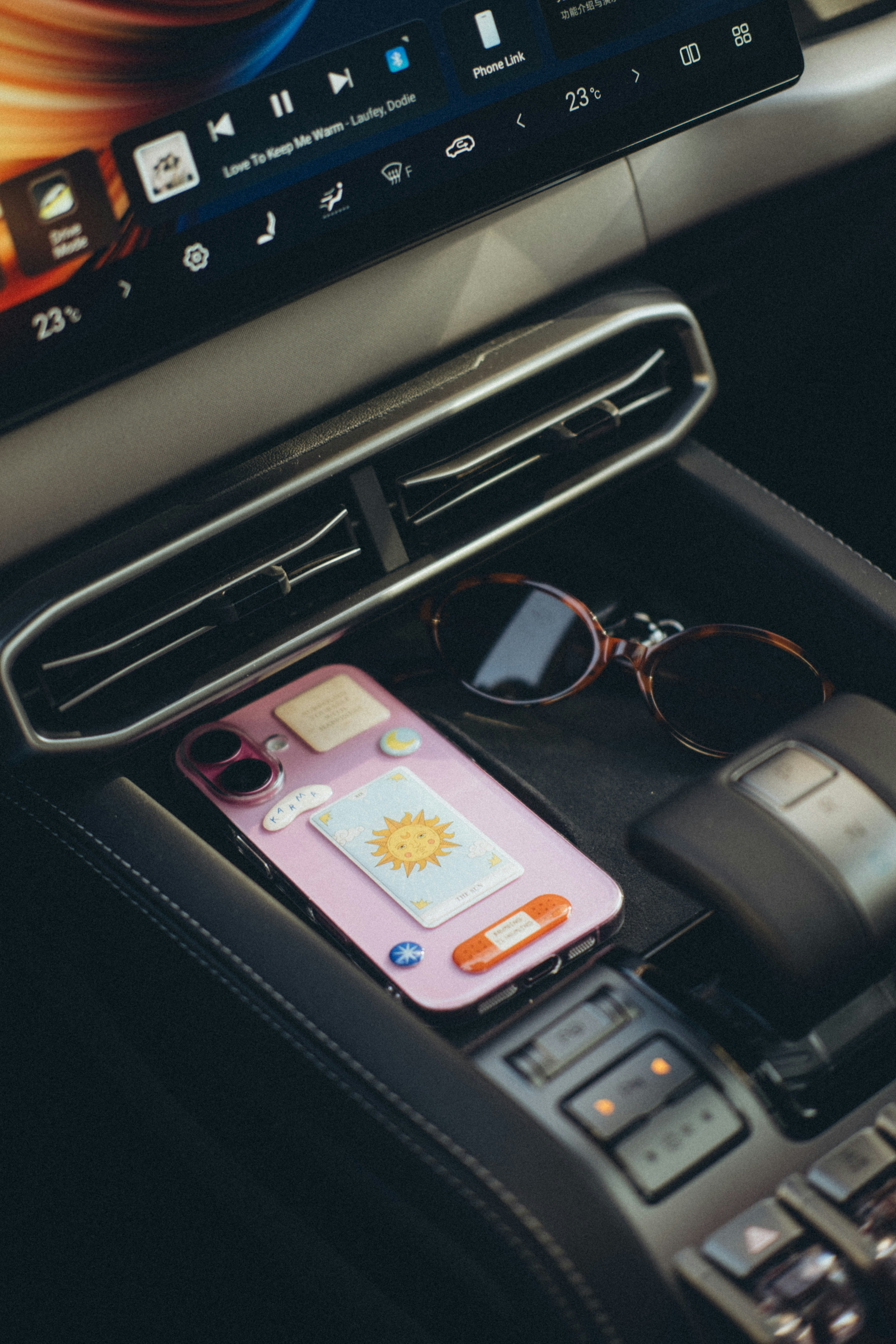 Phone and sunglasses in a car console.