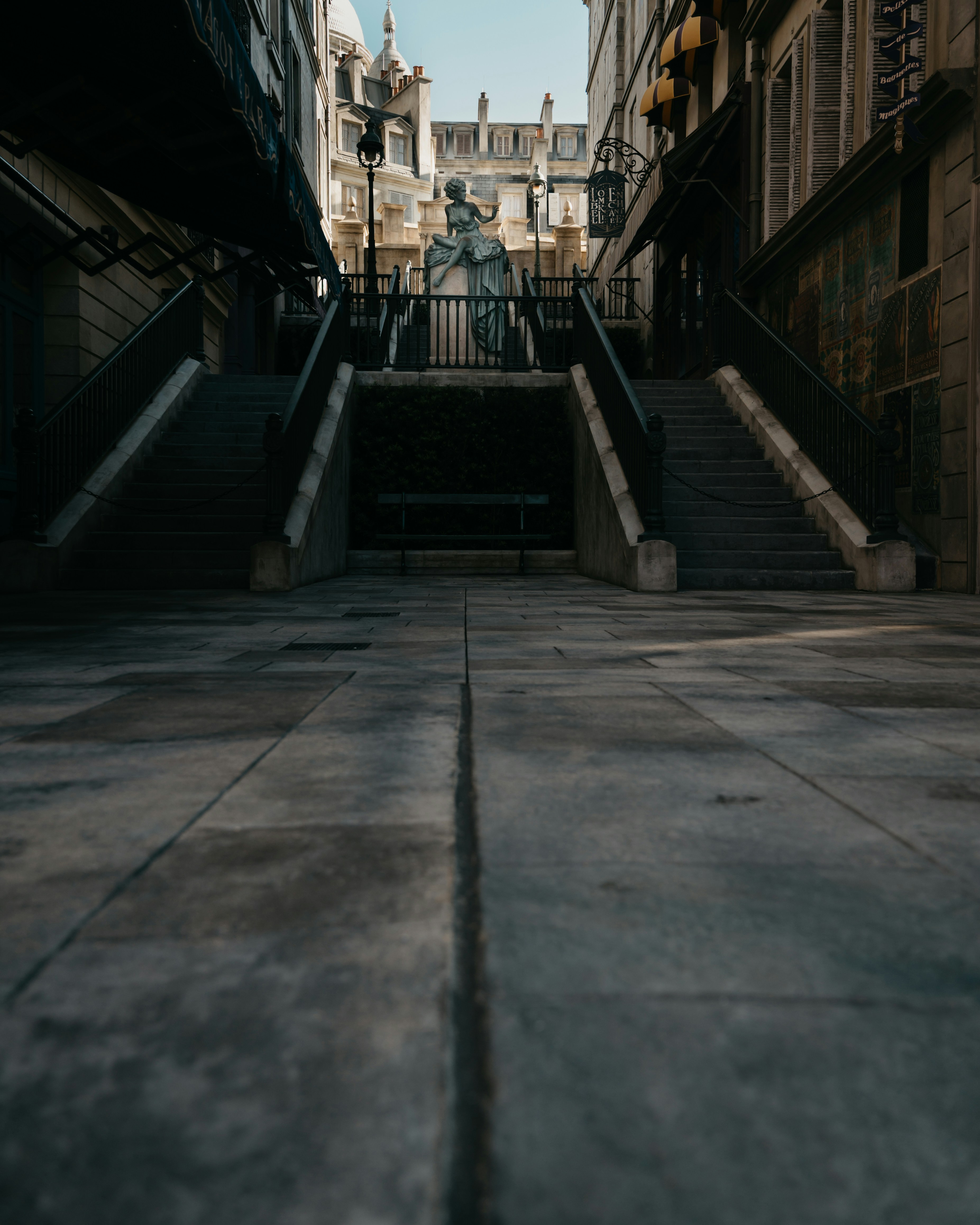 A tranquil courtyard featuring a statue, flanked by staircases leading to a serene backdrop of architectural details.